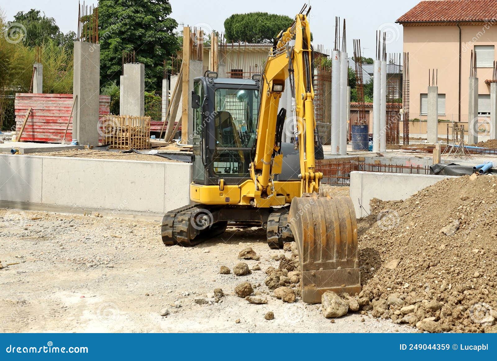 Compact Excavator At Work Among The Foundations And The Pillars Of A ...