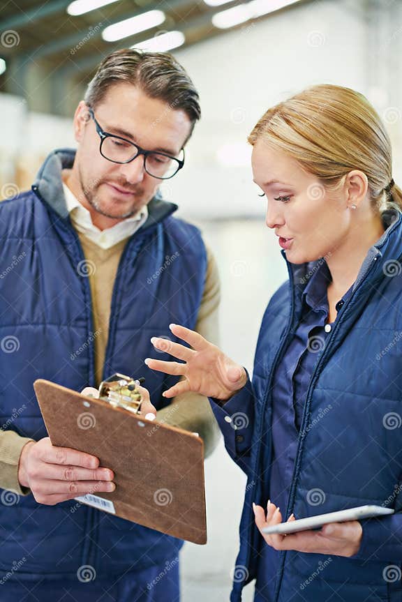 Comparing Their Paperwork. Two People Looking at Paperwork while ...
