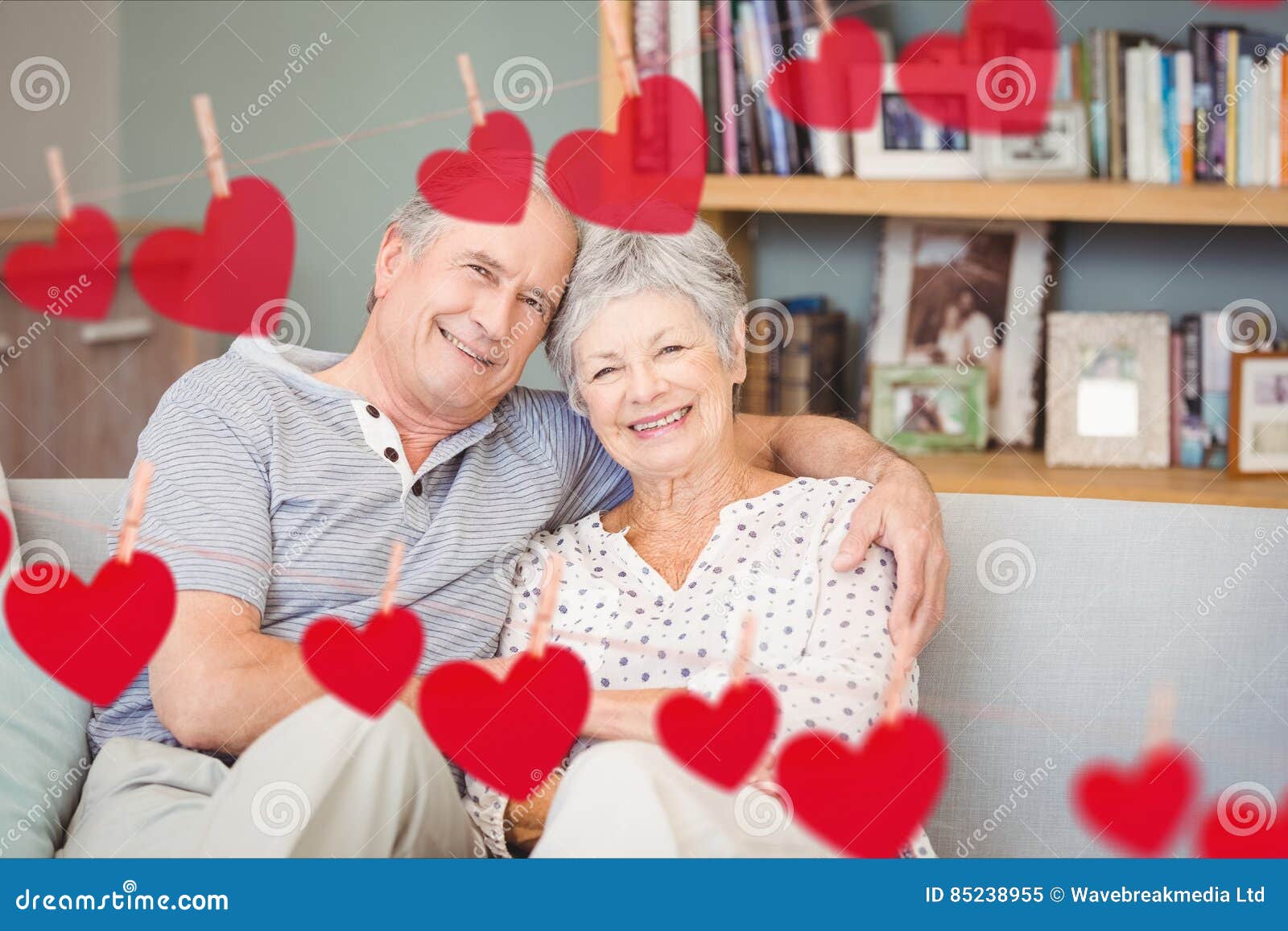 Composite Image Of Red Heart And Senior Couple Embracing On Sofa Stock