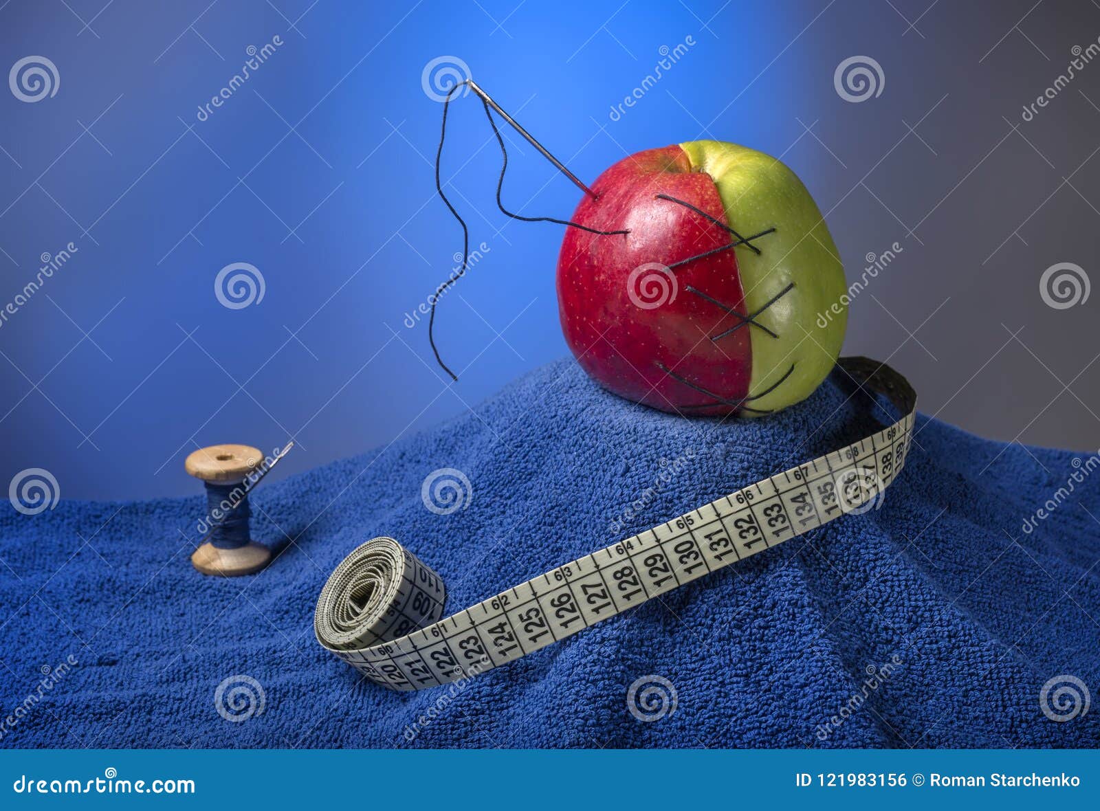 Composition: Green-red Apple with the Needle and Thread on a Blue Towel ...