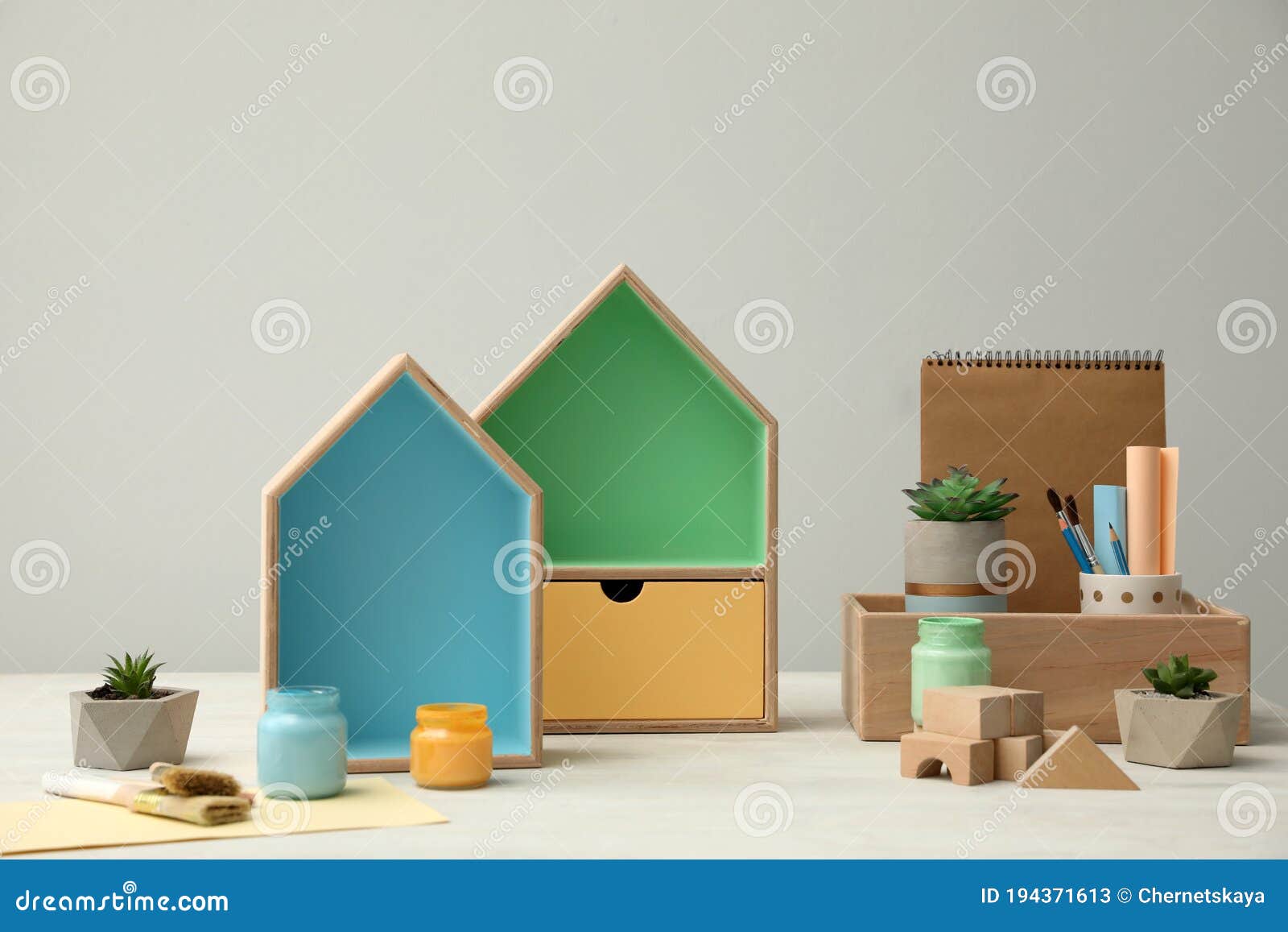 Composition with House Shaped Shelves and Jars of Paints on Table ...