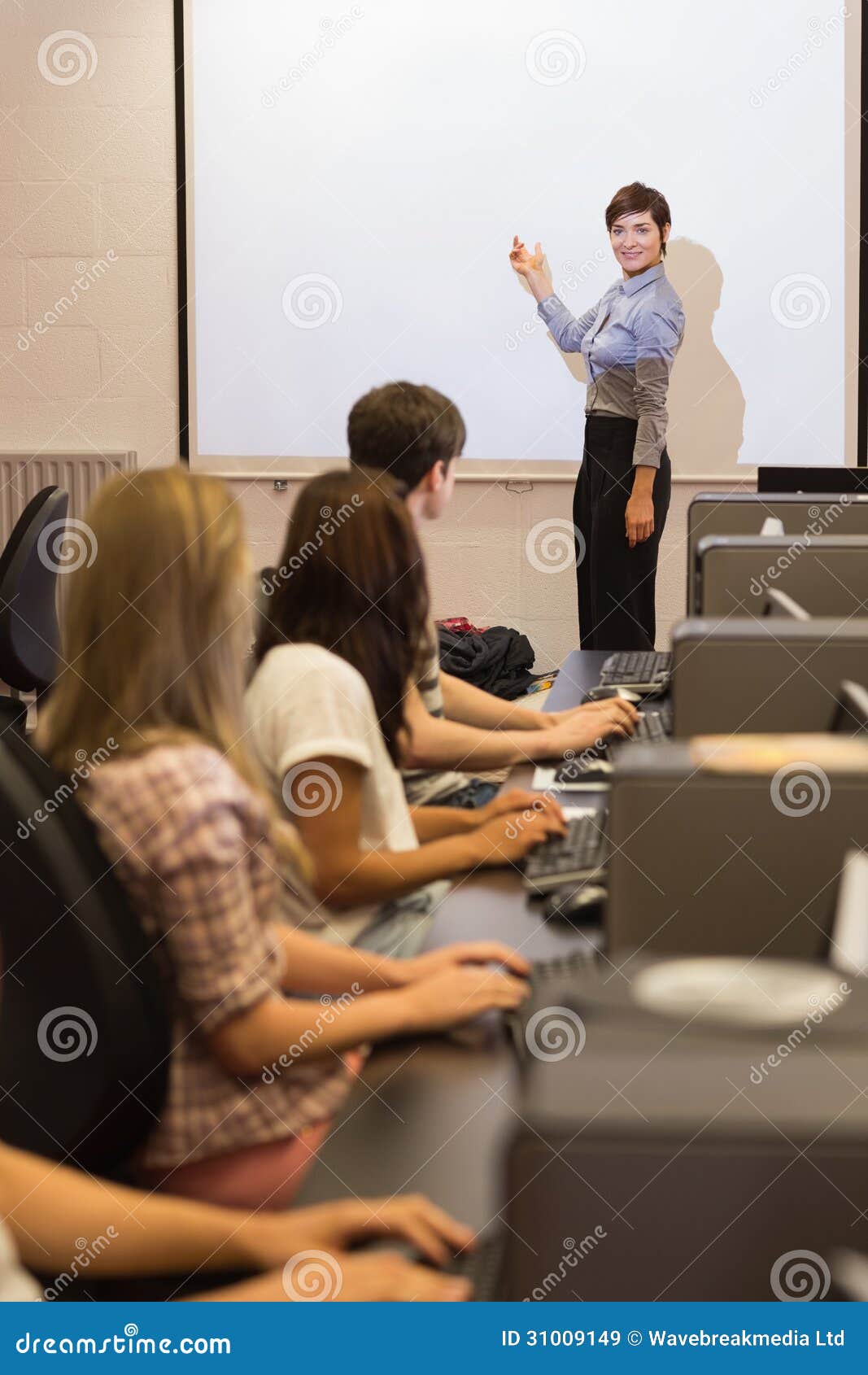 Computer Class Looking at Teacher Pointing on Projection Screen Stock ...