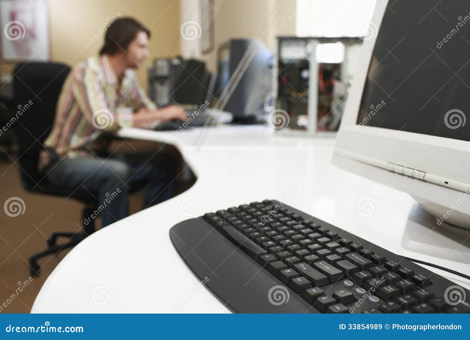 Computer on Desk with Man Working in Background Stock Image - Image of ...