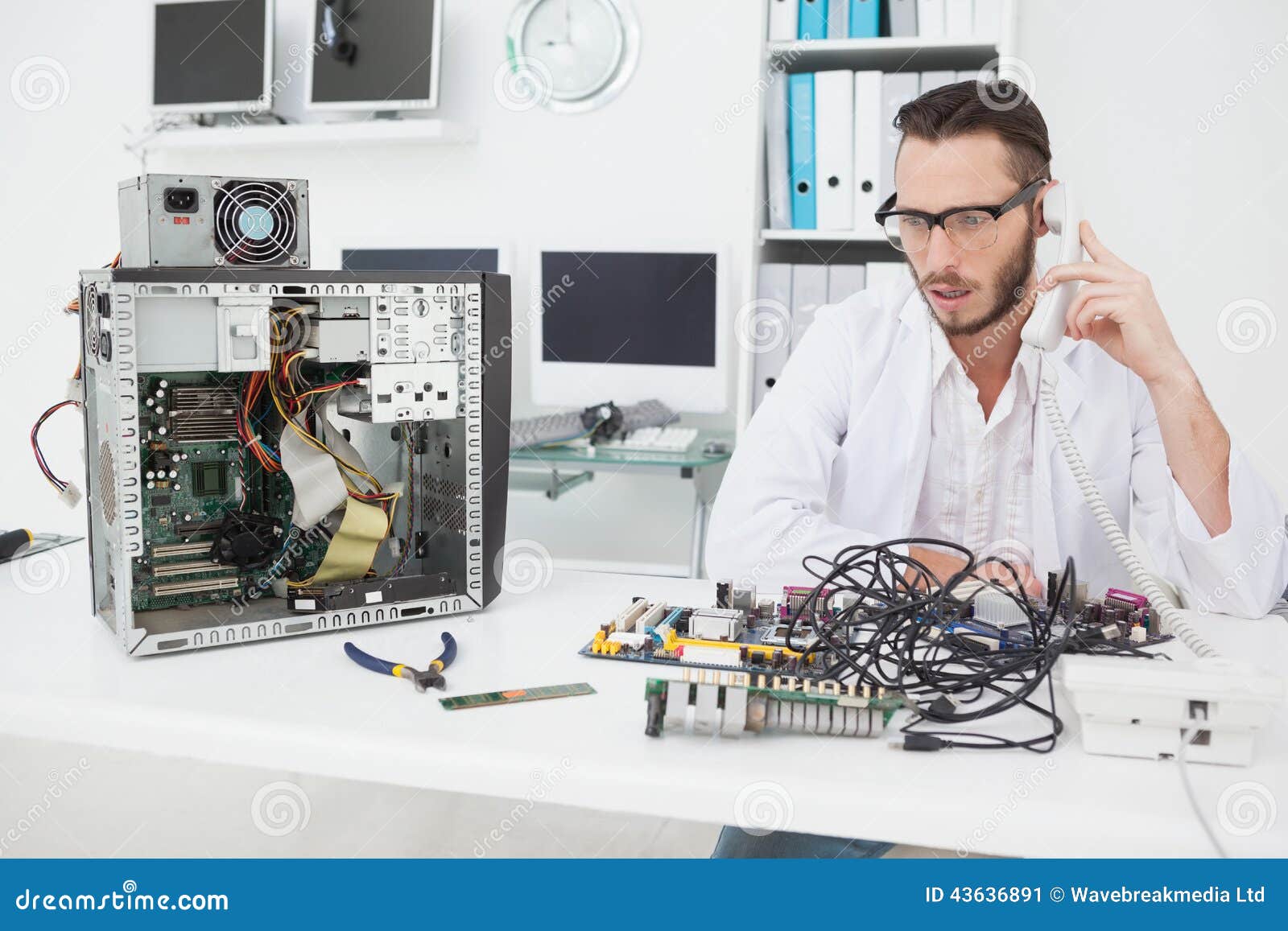 Computer Engineer Looking at Broken Device and Making a Phone Call ...