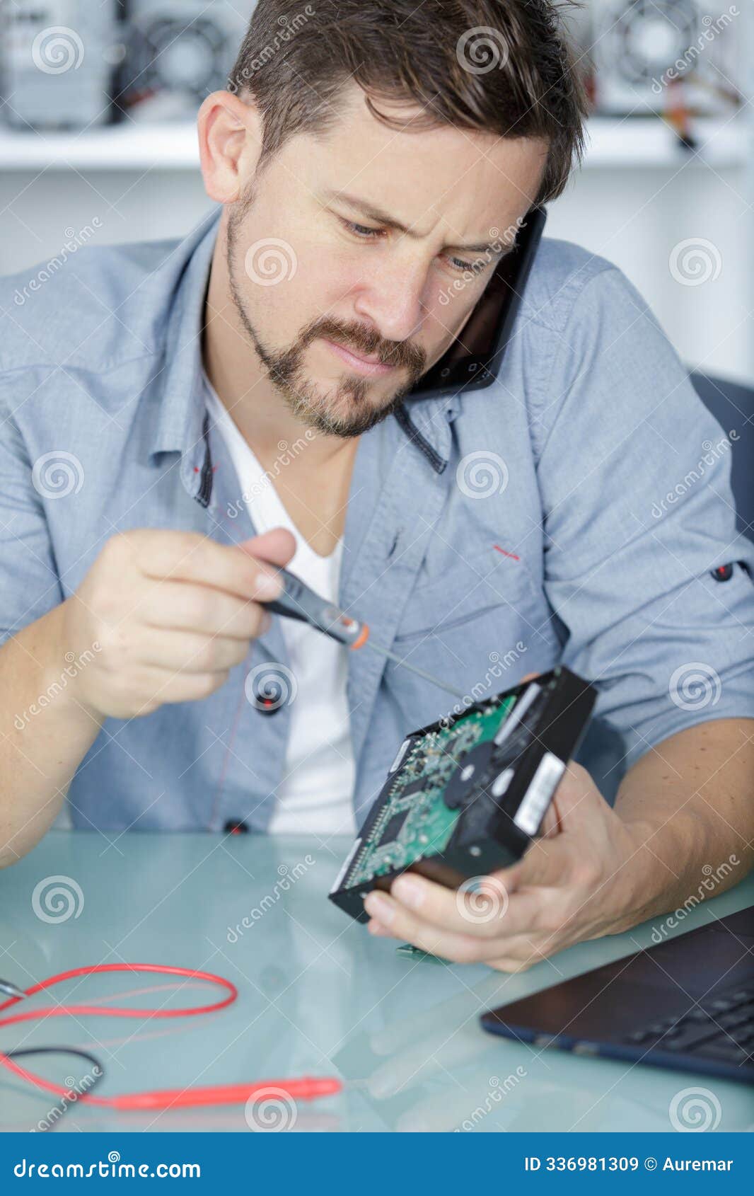 Computer Engineer Talking on Smartphone while Unscrewing Laptop ...
