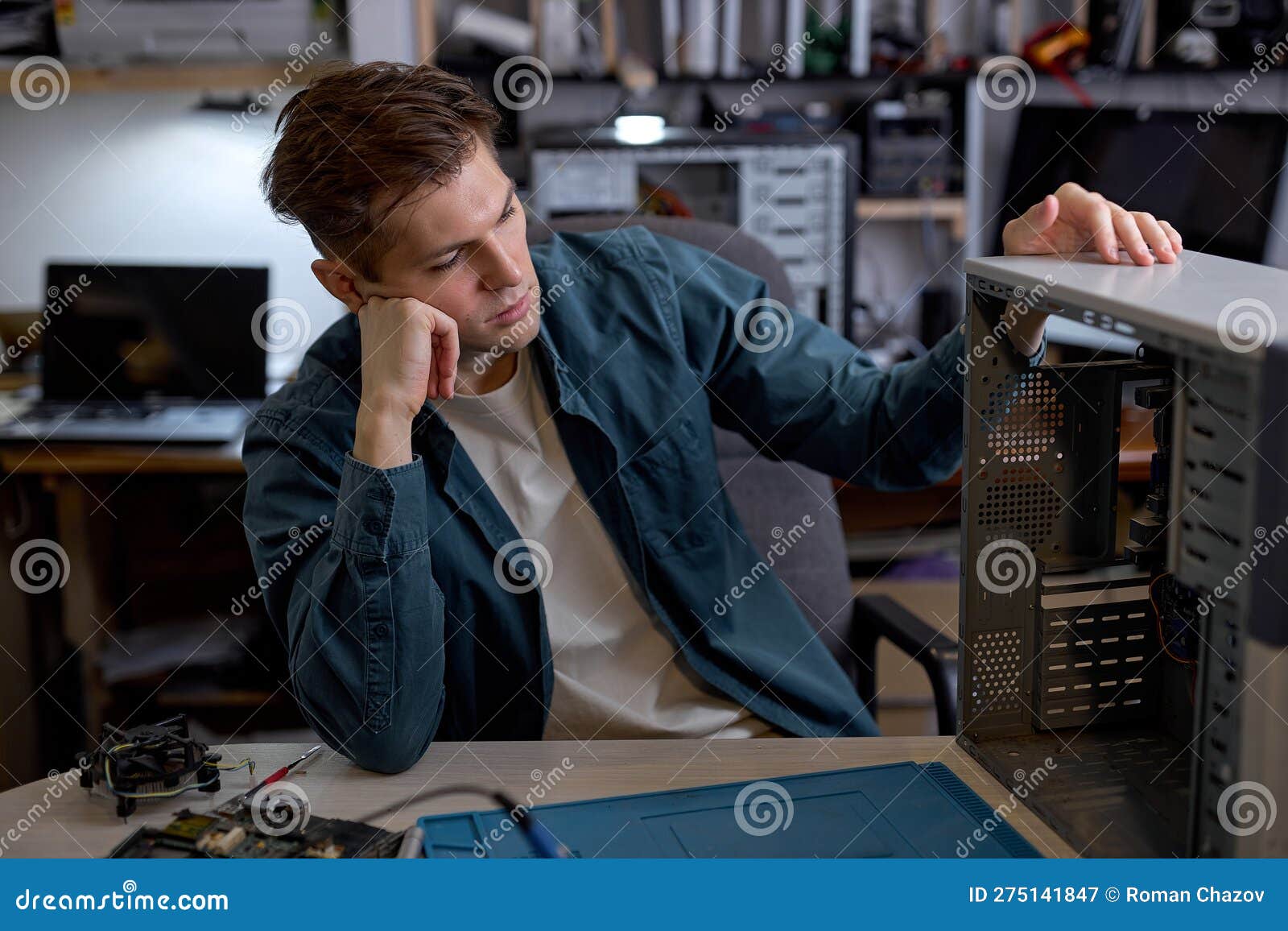 Computer Repairman Checking a Computer Component after Disassembling it ...
