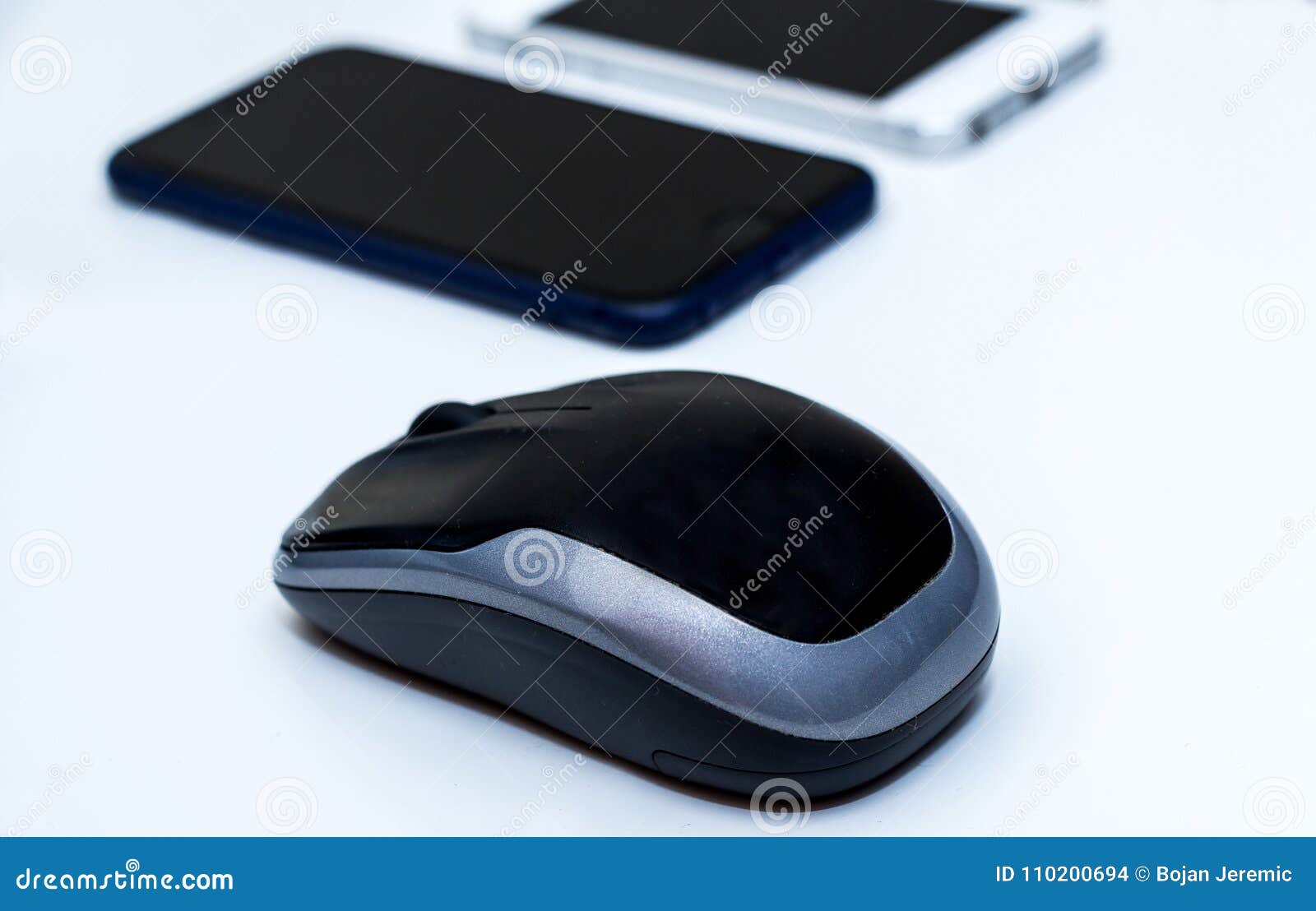 Computer Wireless Mouse and Two Mobile Phones on a White Desk. Stock ...