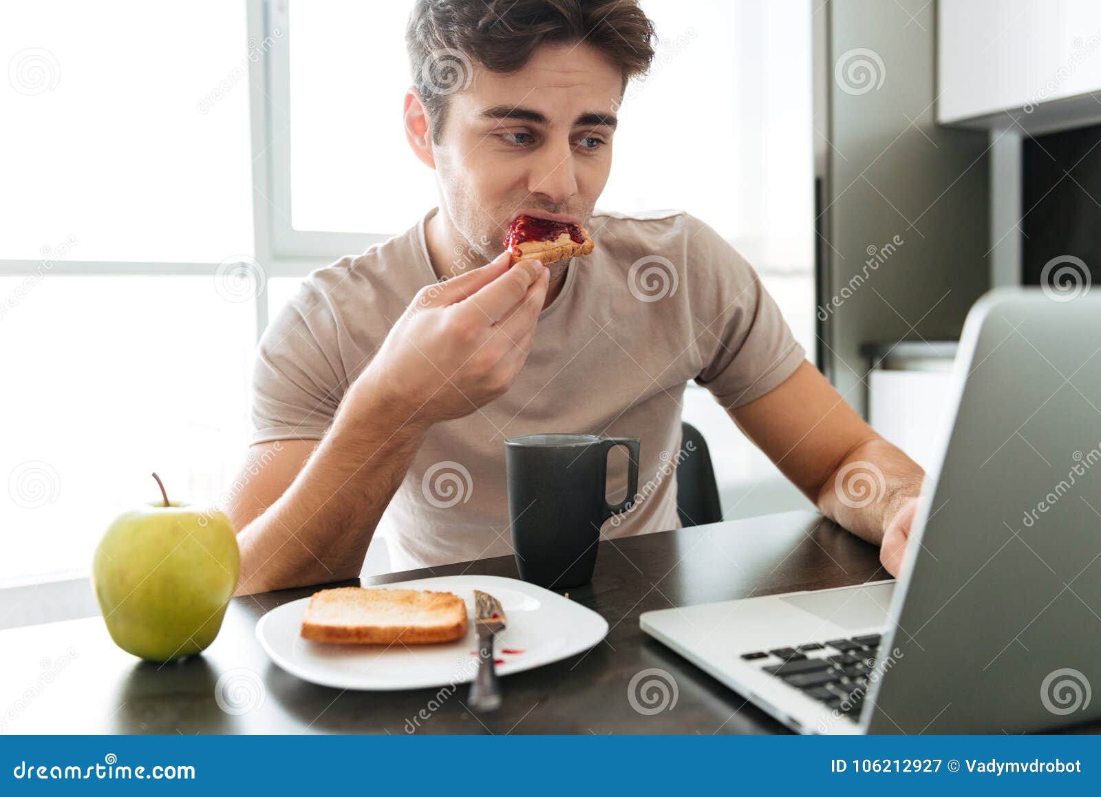 Concentrated Attractive Man Using Laptop while Eating Breakfast Stock ...