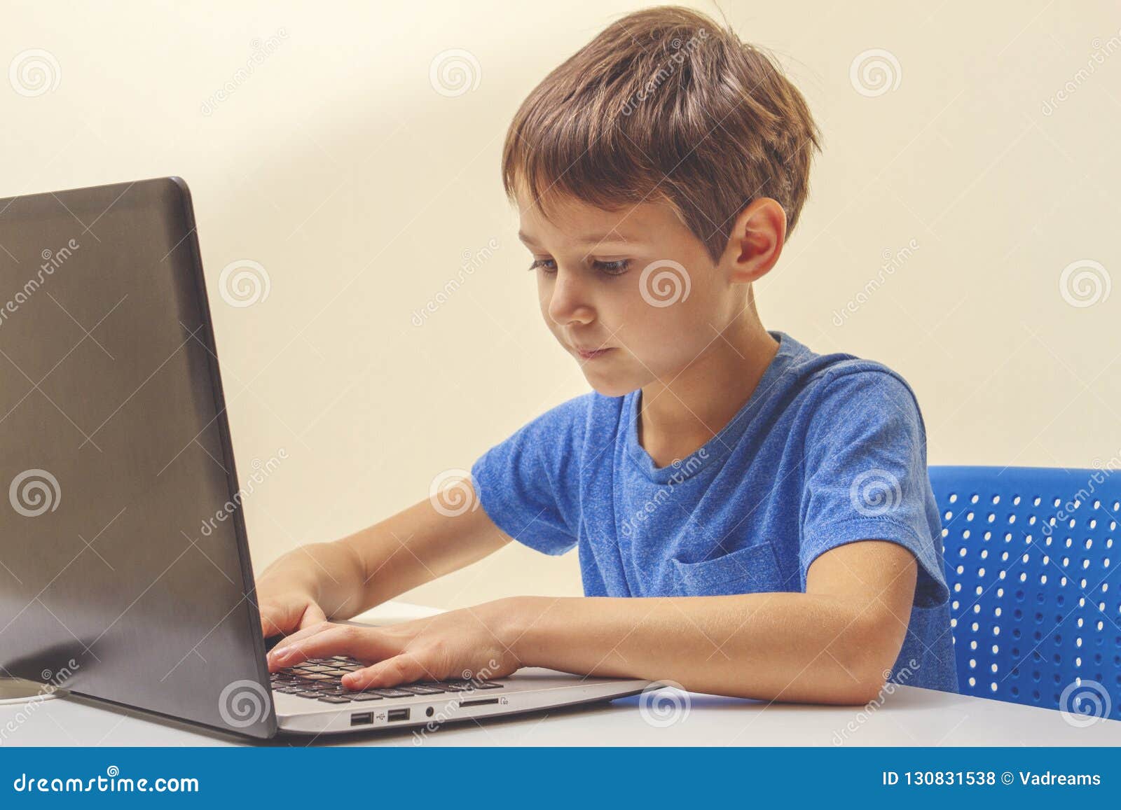 Concentrated Boy Sitting at Desk with Laptop Computer and Doing ...