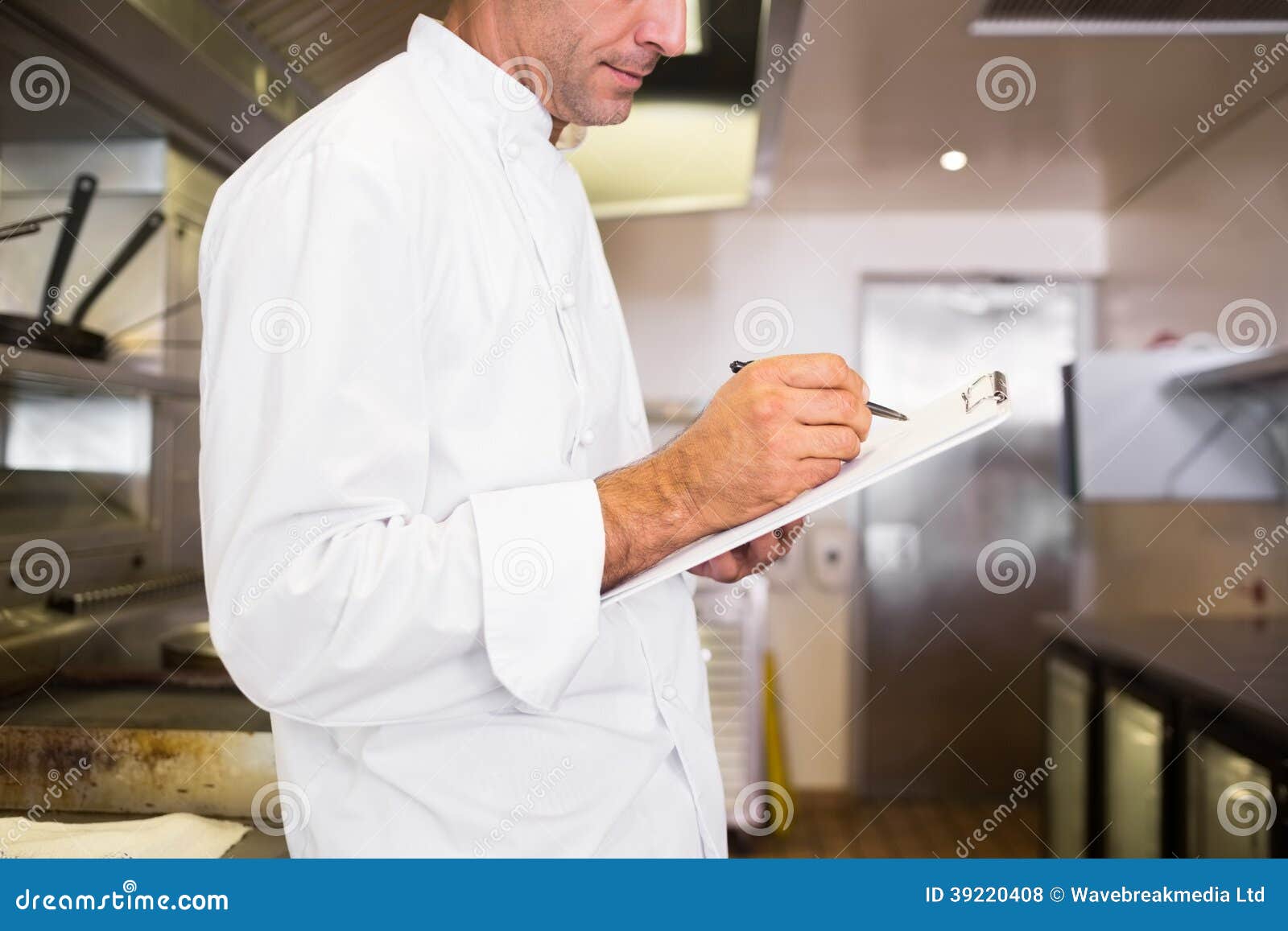 Concentrated Male Cook Writing on Clipboard in Kitchen Stock Photo ...