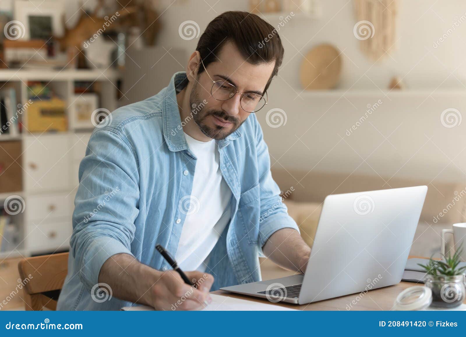 Concentrated Man Sitting by Computer Taking Notes of Distant Lecture ...