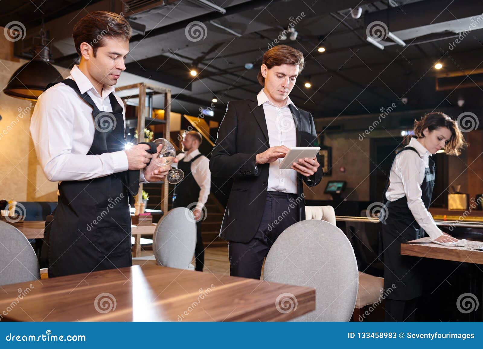 Concentrated Restaurant Manager Checking Online Records on Table Stock ...