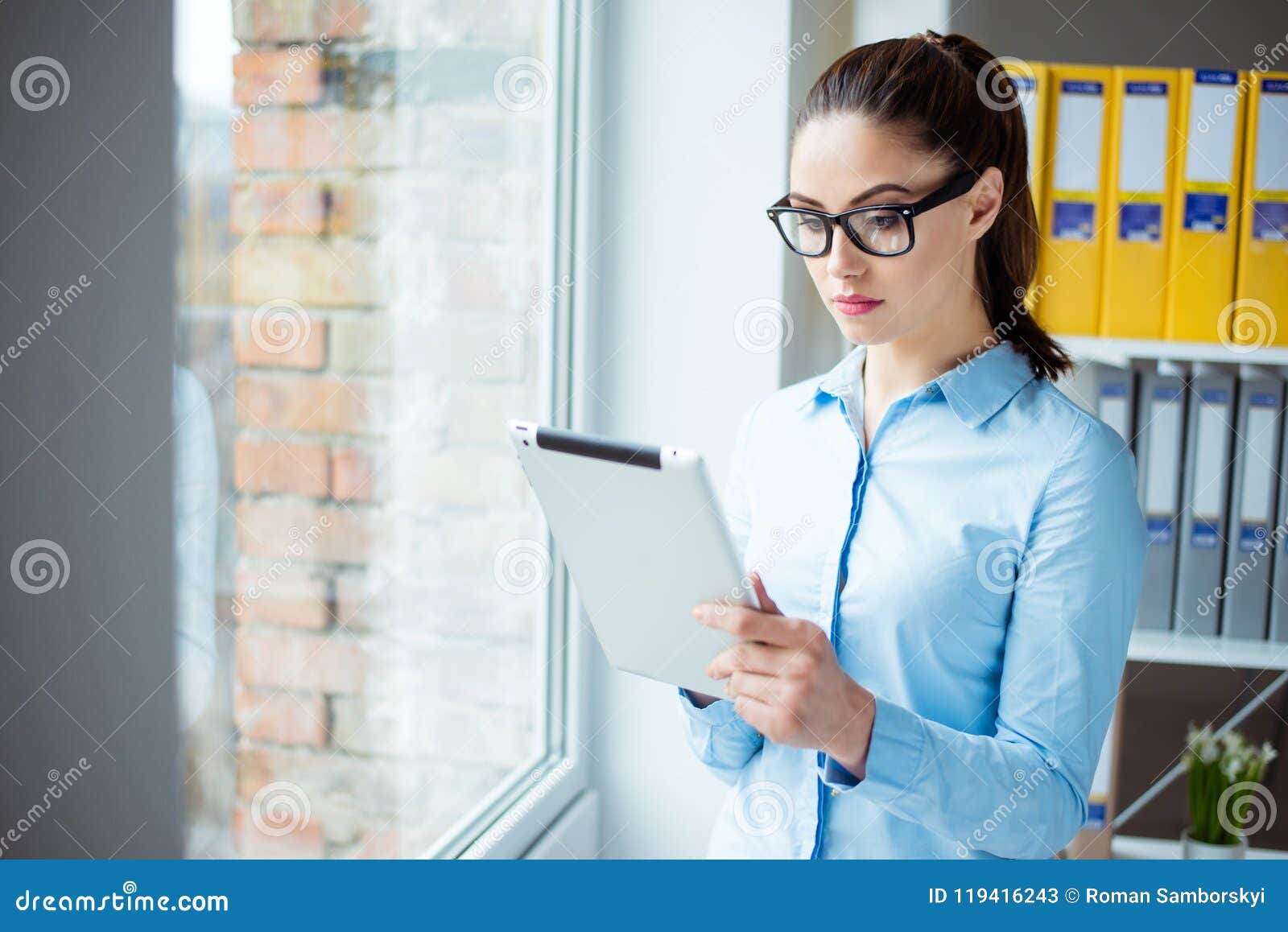 Concentrated Woman Standing Near The Window At Her Office Hilding