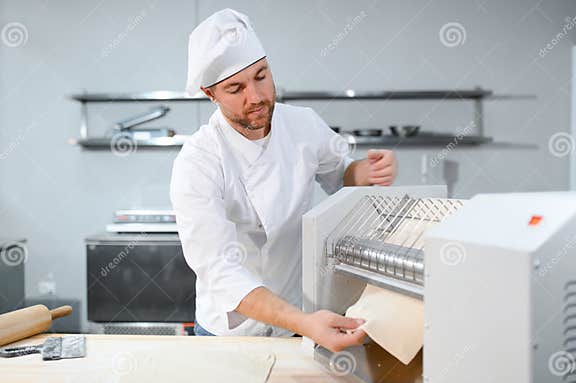 Concentrated at Work. Handsome Chef Rolling a Dough through Pasta ...