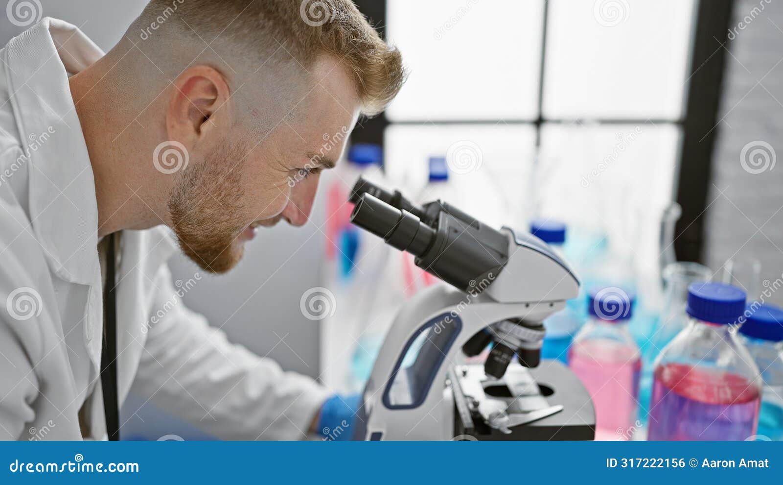 A Concentrated Young Bearded Man Wearing a White Lab Coat Working with ...