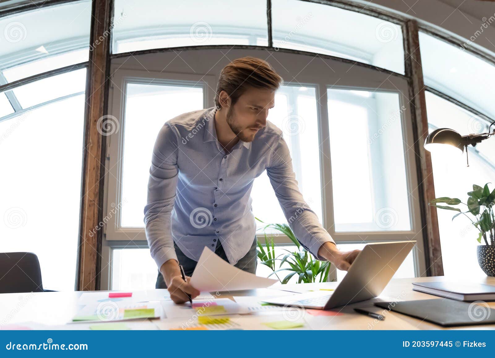 Concentrated Male Project Manager Standing by Desk Involved in ...