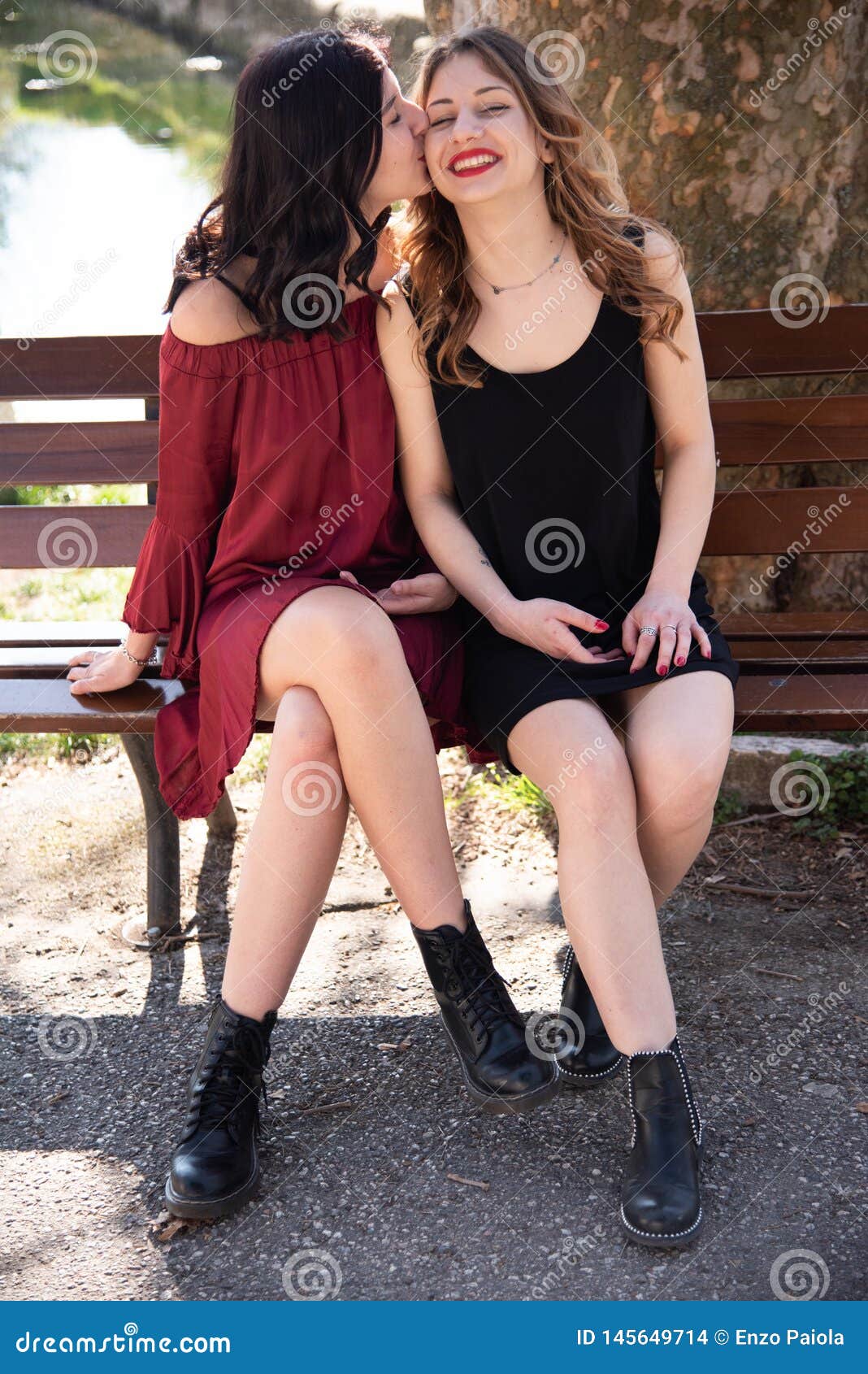 Close Up Of Two Friends Sitting On A Bench By A Lake A Blonde The