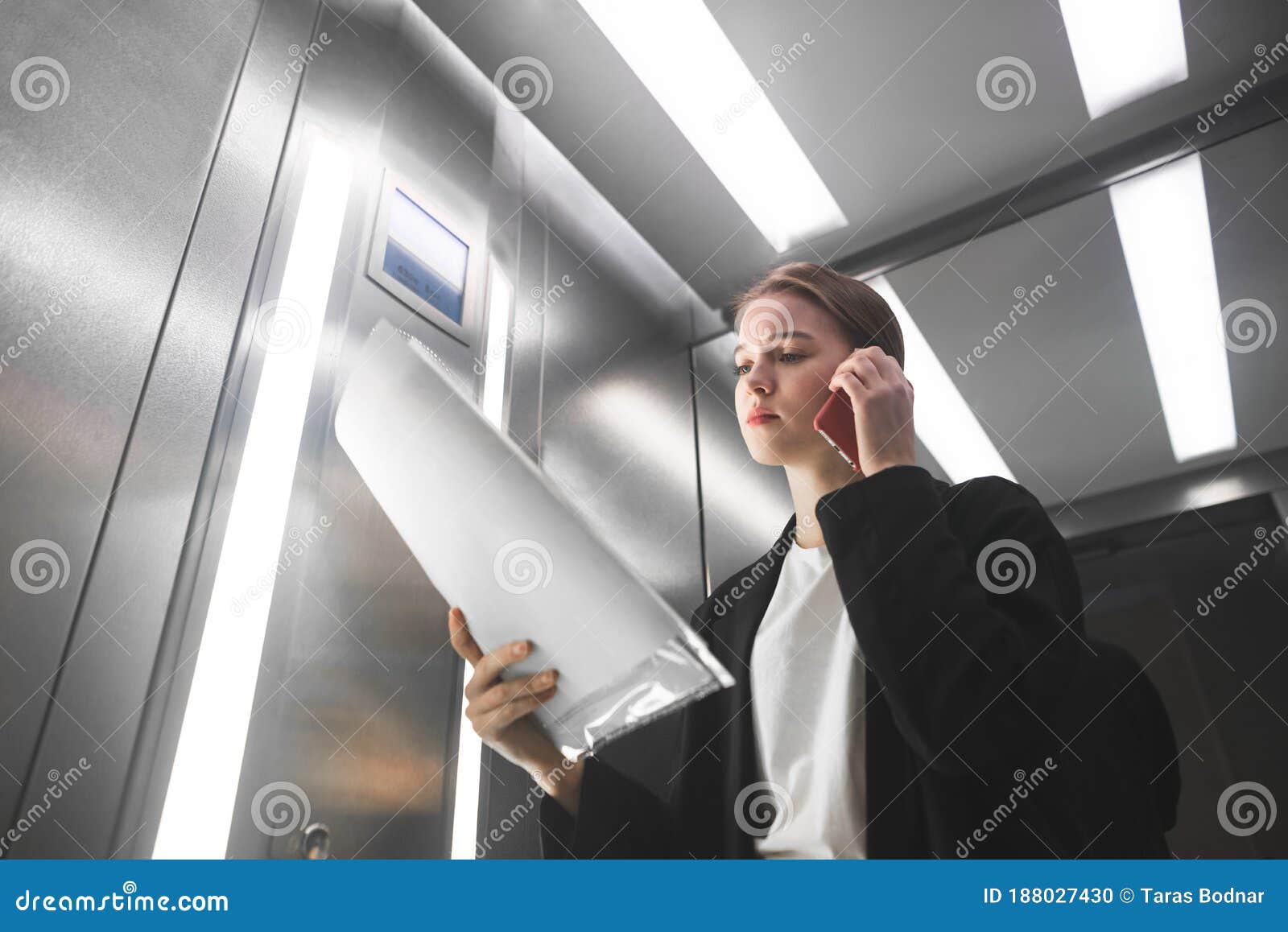 Concerned Female Office Worker is Speaking on the Phone and Checking ...