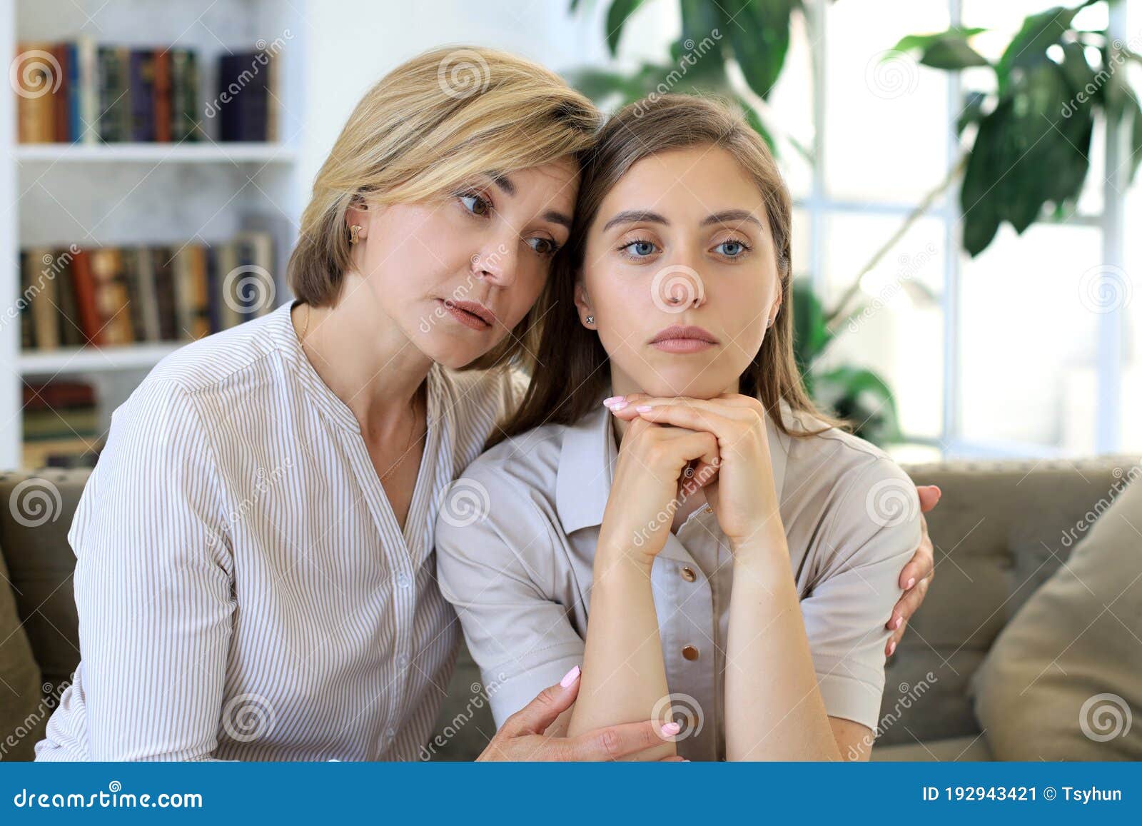 Concerned Middle Aged Mother And Adult Daughter Sit On Couch Having