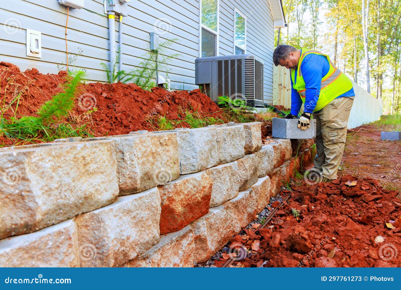 Concrete Blocks are Mounted To Retaining Wall by a Construction Worker ...