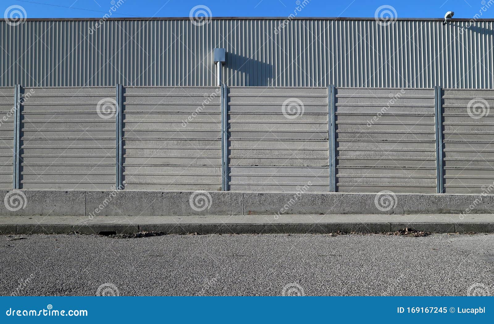 Concrete Surrounding Wall, with a Gray Metallic Cladding Facade Behind ...