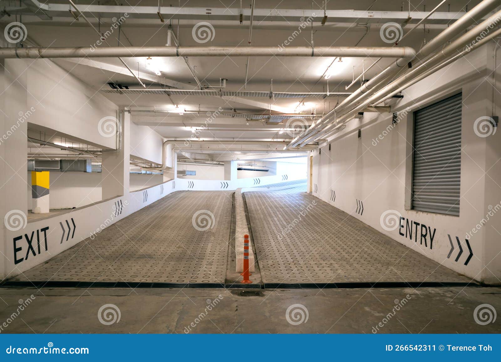 A Concrete Vehicle Ramp Inside a Building with Entry and Exit Signs ...