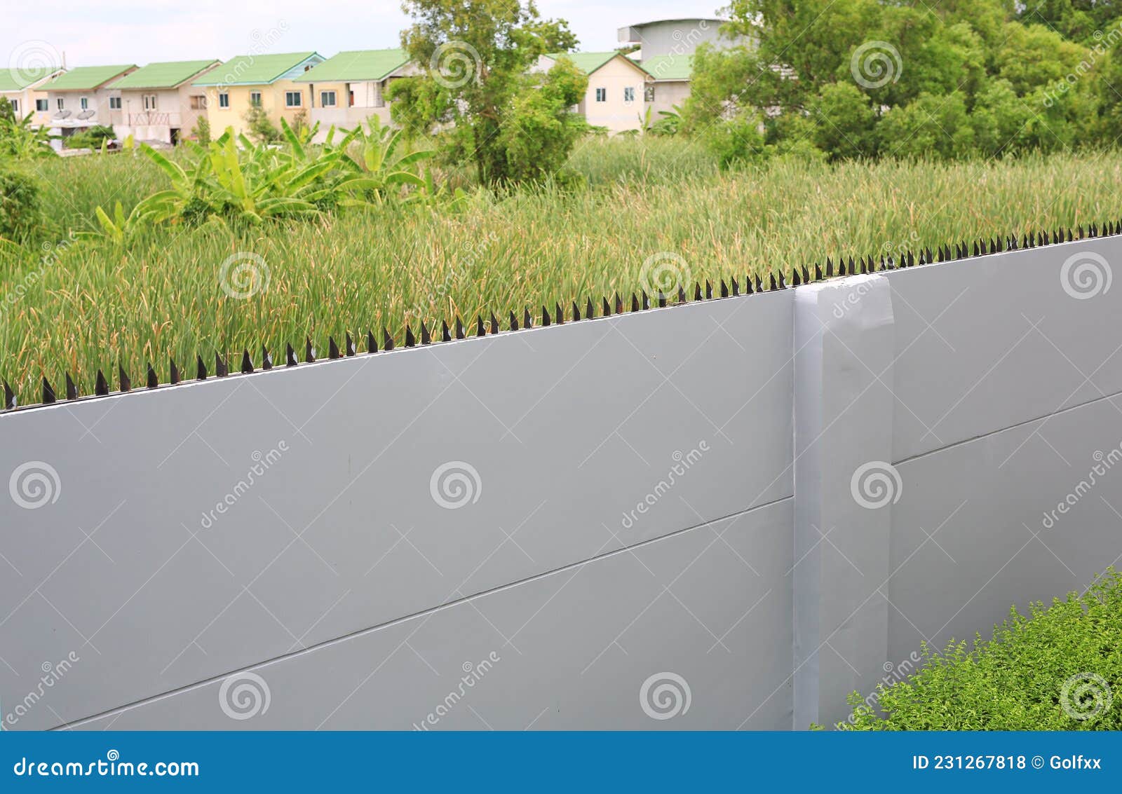 Concrete Wall with Black Sharp Iron Bar Against Green Field Background ...