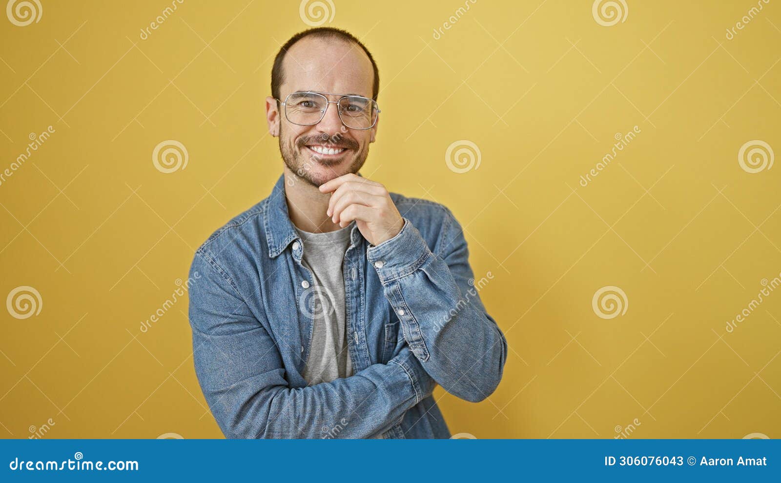 Confident Bald Man with Beard Smiling in Front of a Yellow Wall Wearing ...