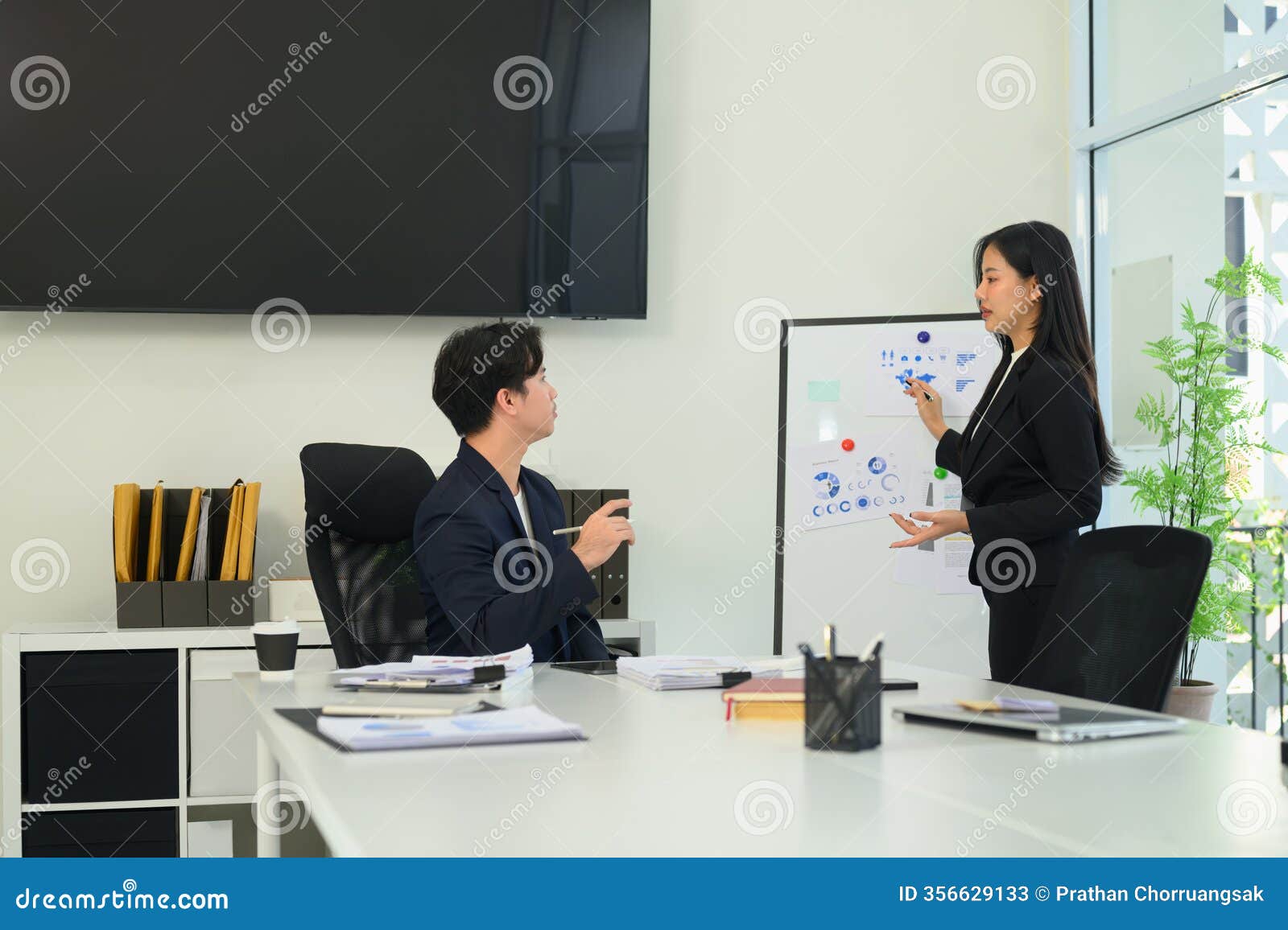 Confident Female Team Leader Presenting Charts and Data on a Whiteboard ...