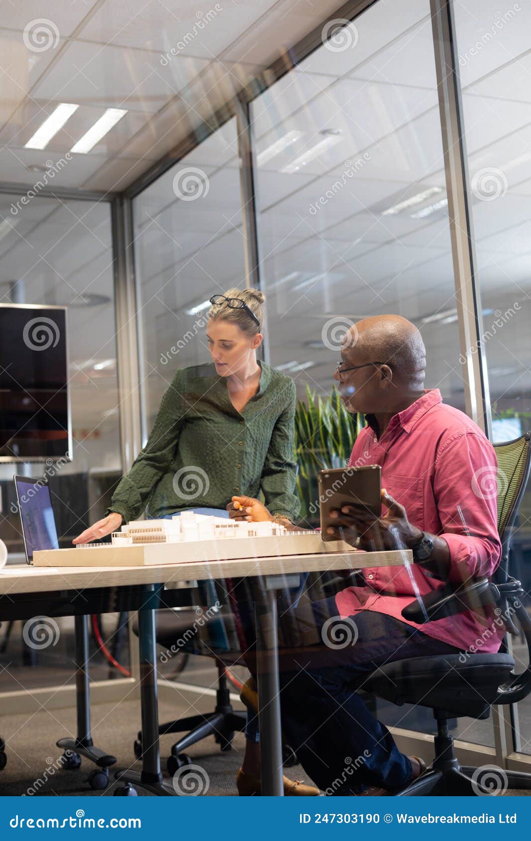 Confident Multiracial Architects Discussing Over Model At Desk In ...