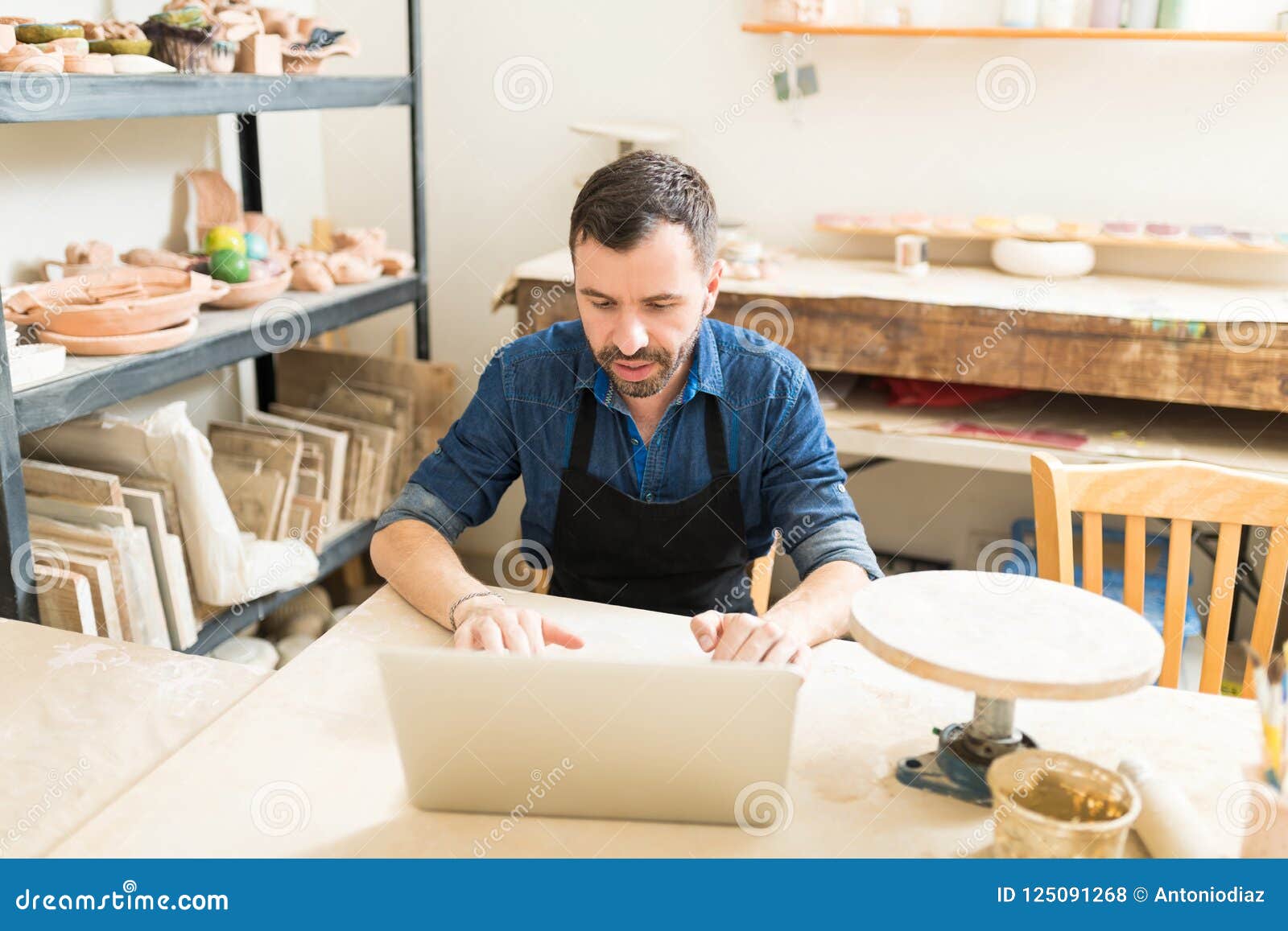Confident Potter Using Laptop Computer at Table in Studio Stock Photo ...
