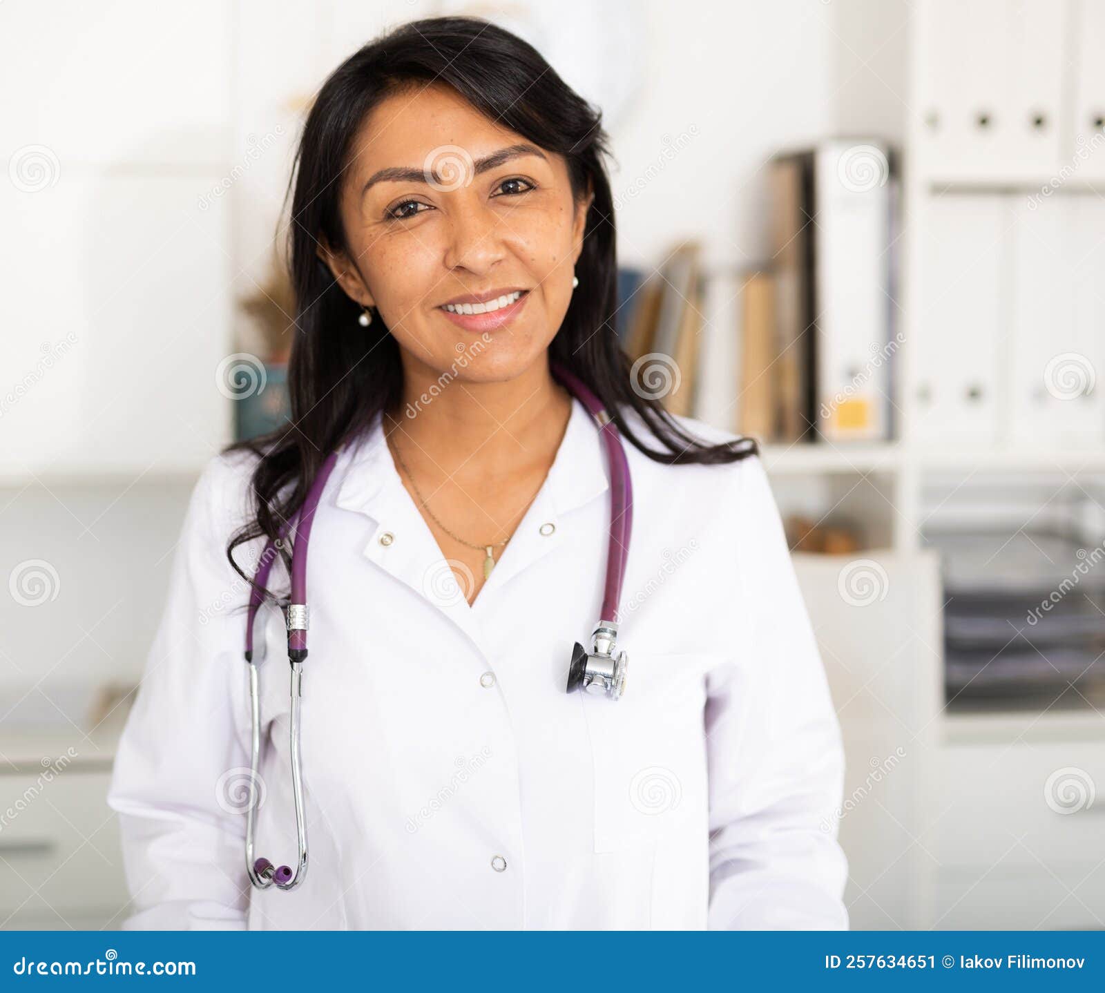 Confident Smiling Female Doctor In White Lab Coat In Medical Office