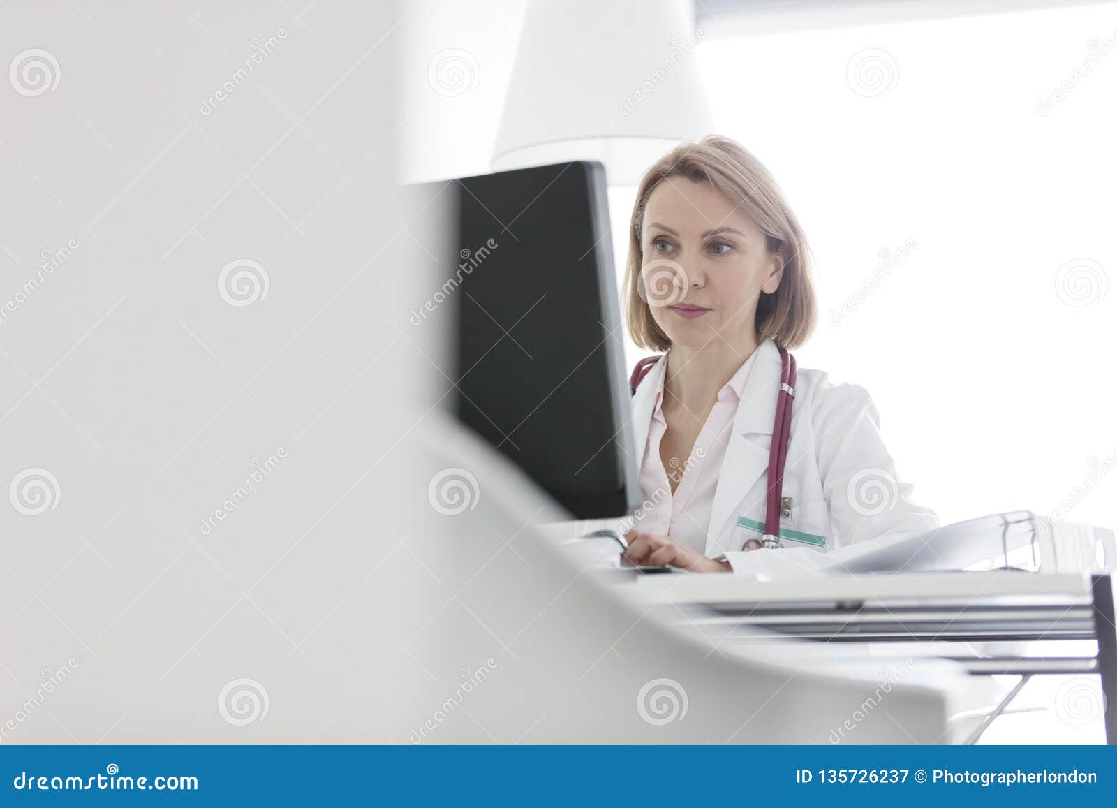Confident Woman Using Computer at Desk in Hospital Stock Image - Image ...