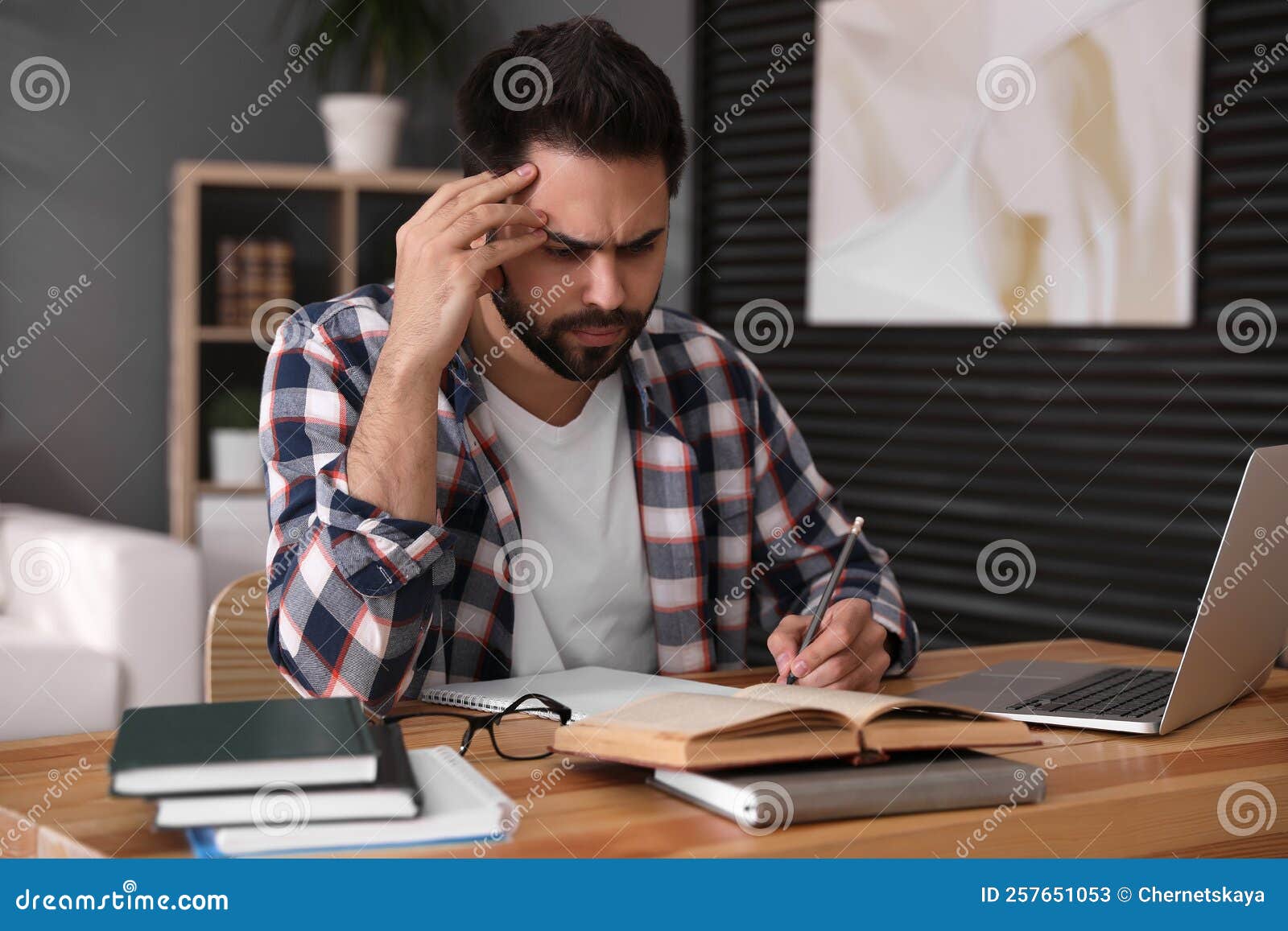 Confused Young Man Writing Down Notes during Webinar at Table in Room ...