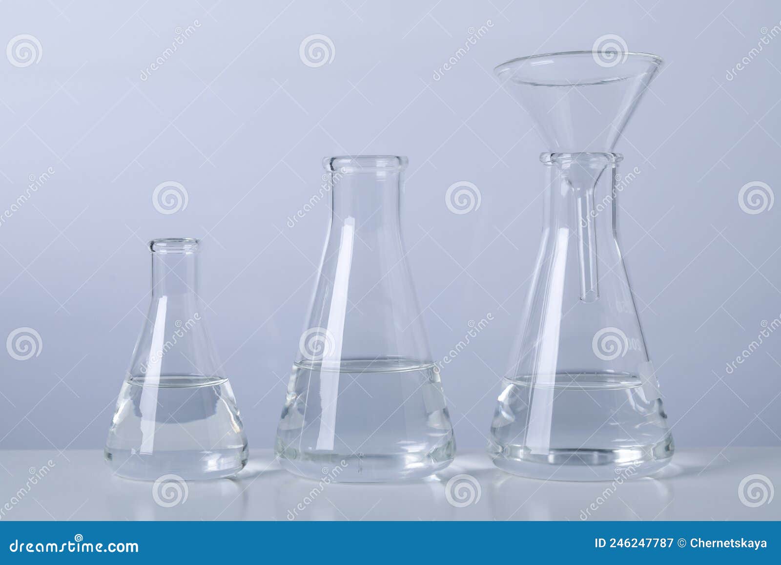 Conical Flasks with Transparent Liquid and Funnel on Table Against ...