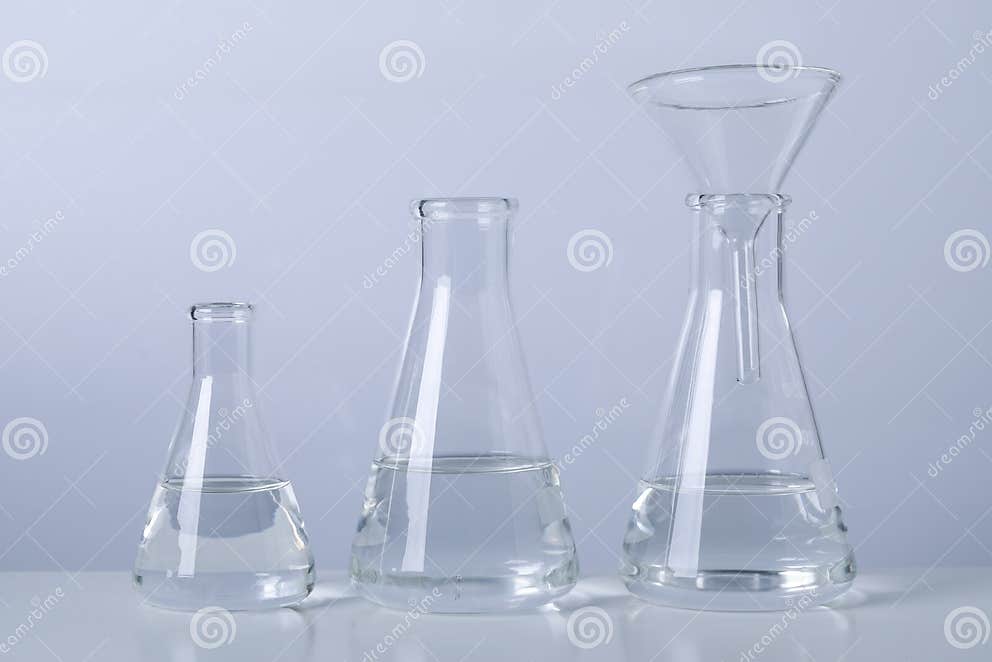 Conical Flasks with Transparent Liquid and Funnel on Table Against ...