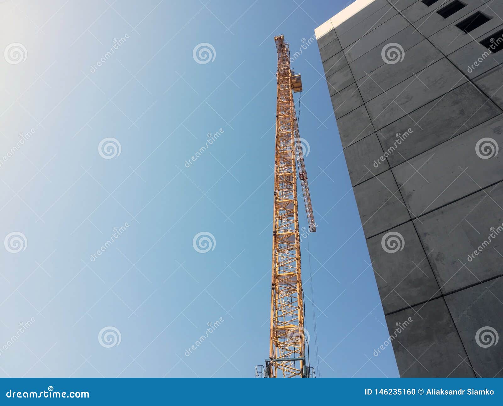 Construction Crane Rises Above the Building. Bottom Up View on Blue Sky ...