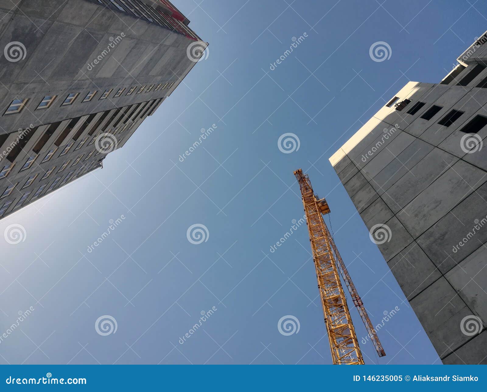 Construction Crane Rises Above Two Buildings. Bottom Up View on Blue ...