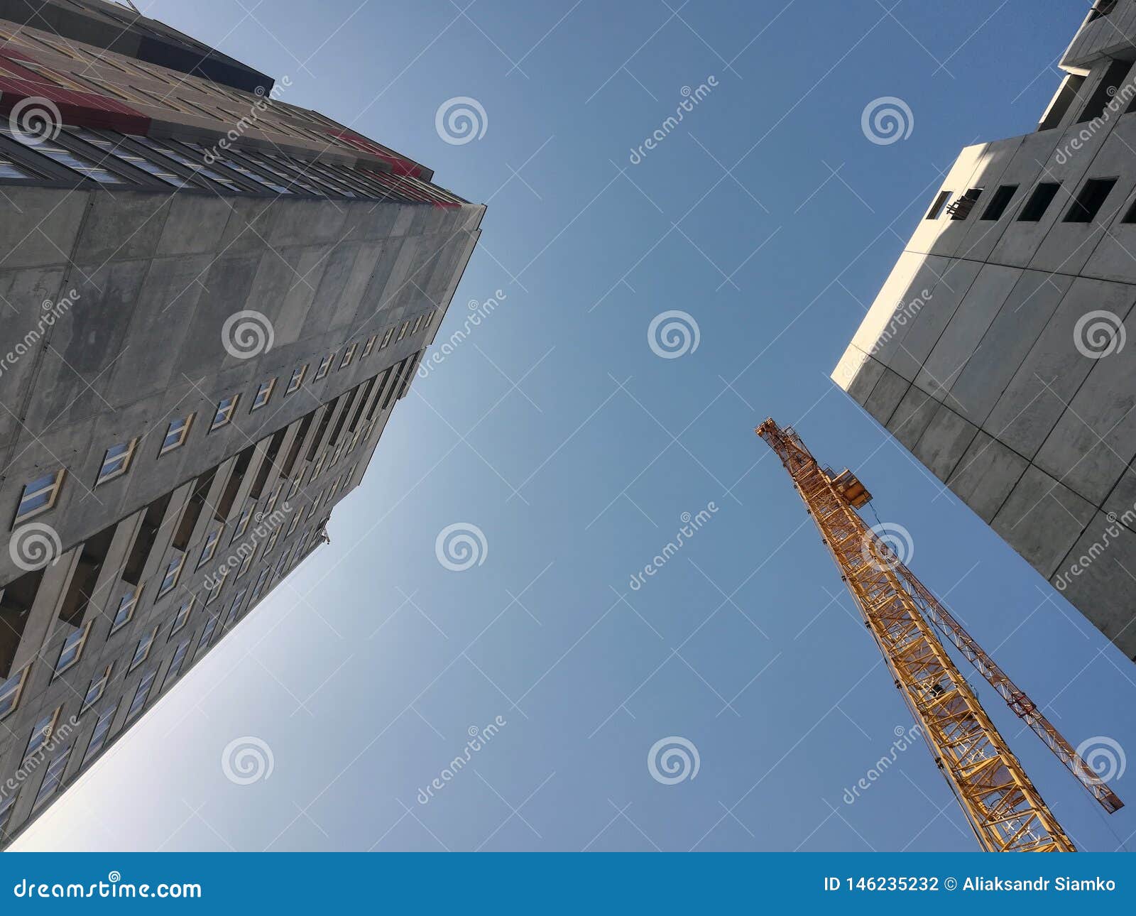 Construction Crane Rises Above Two Buildings. Bottom Up View on Blue ...