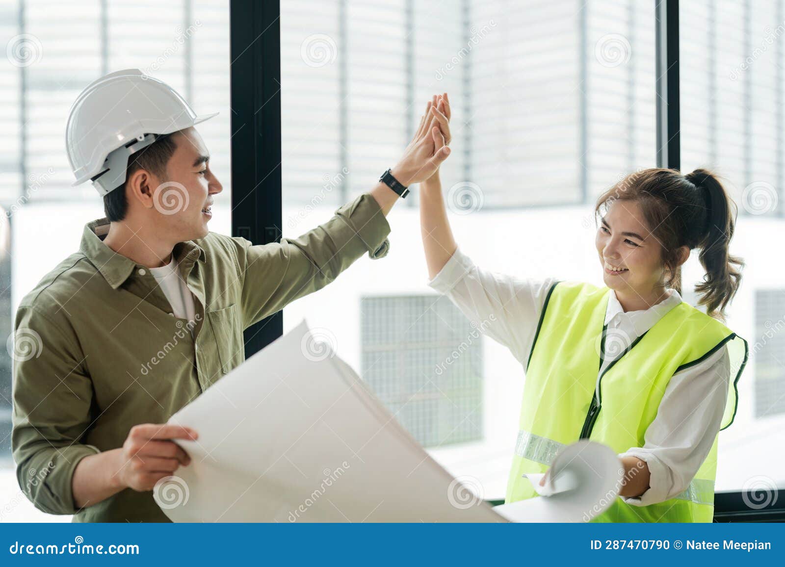 Construction Engineer with Blueprint Making High Five while Standing on ...