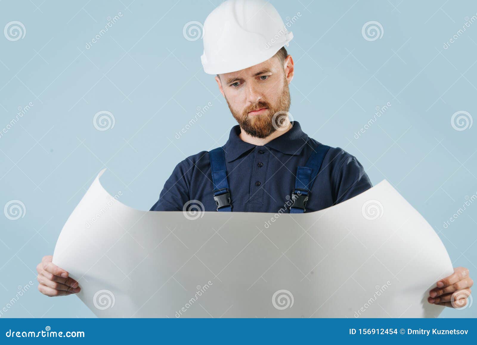 Construction Engineer in a White Helmet and Blue Uniform with a Paper ...