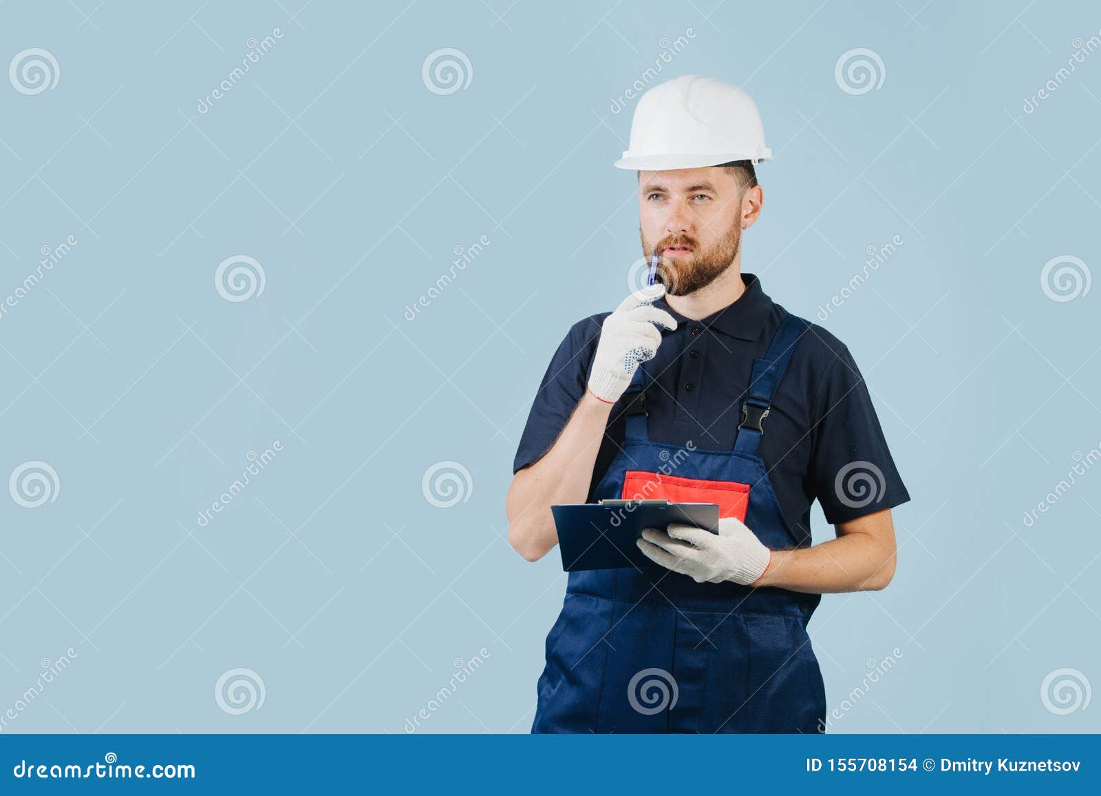 Construction Engineer in a White Helmet and Blue Uniform with a Paper ...