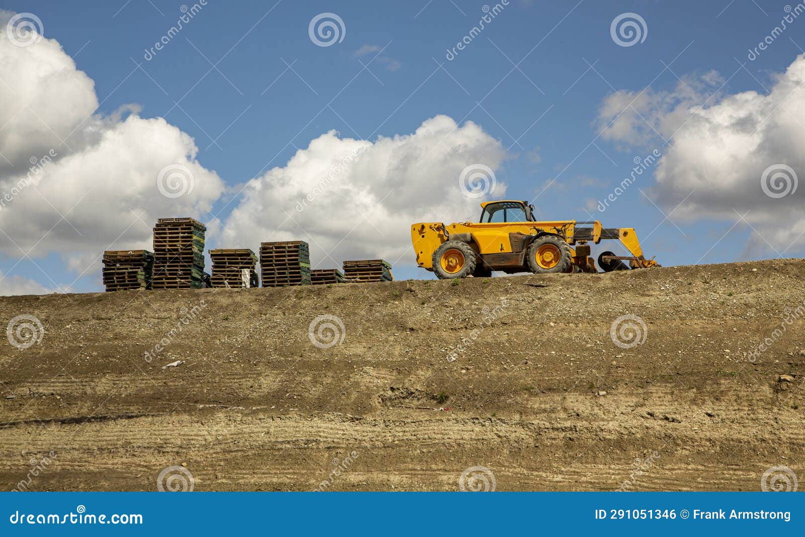 Construction Grading Equipment and Pallets on a Hill Against a Blue Sky ...