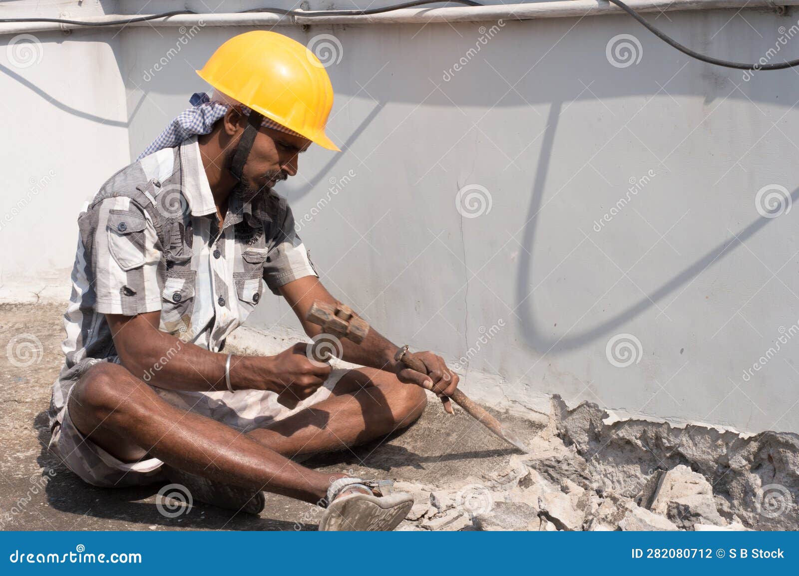 A Construction Labour Working with Hammer and Chisel Wearing Safety ...