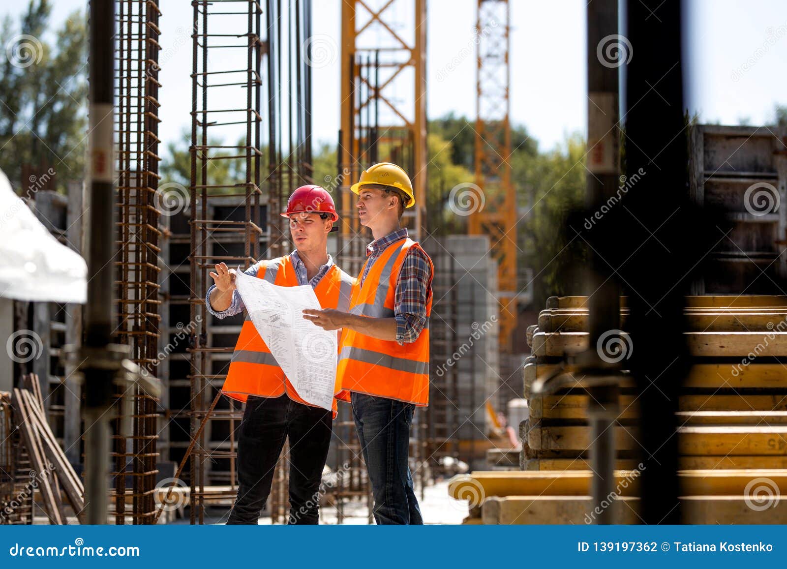 Construction Manager and Engineer Dressed in Orange Work Vests and Hard ...