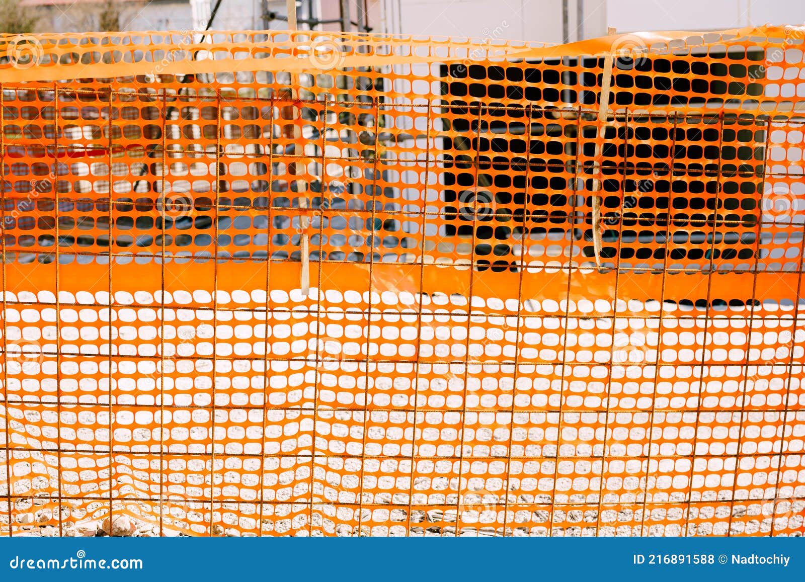 Construction Materials Lie Behind an Orange Construction Grid in a ...