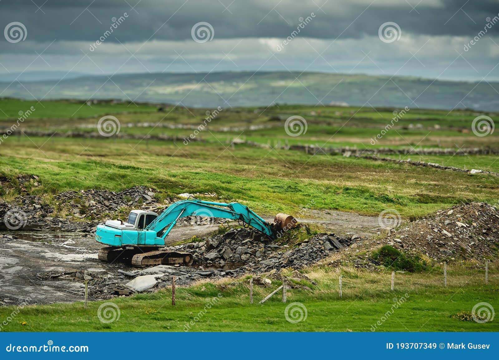 Construction Site in a Field with Blue Color Excavator Working. Dark ...