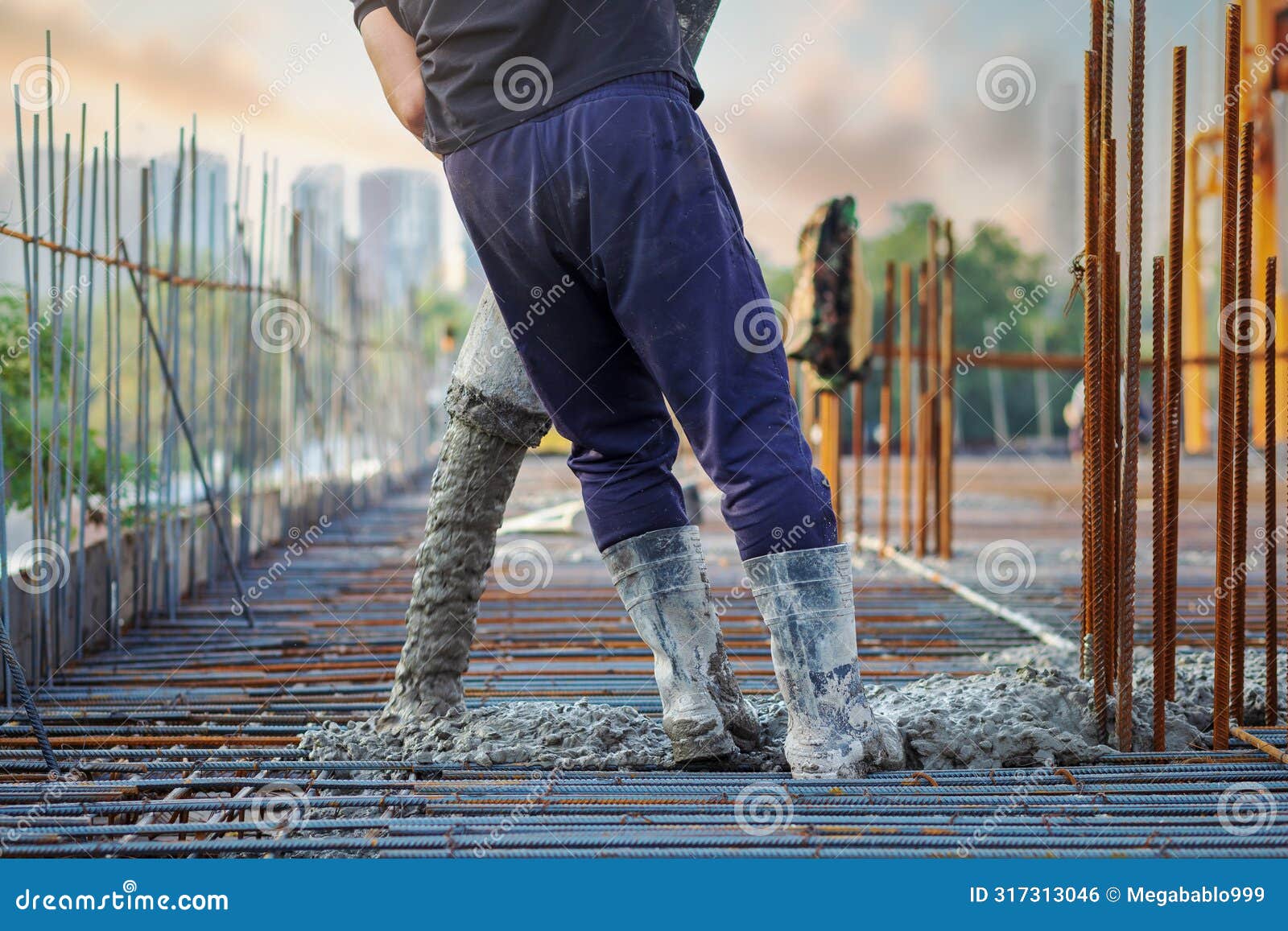 A Construction Site Worker in Rubber Boots Manipulates a Concrete Pump ...