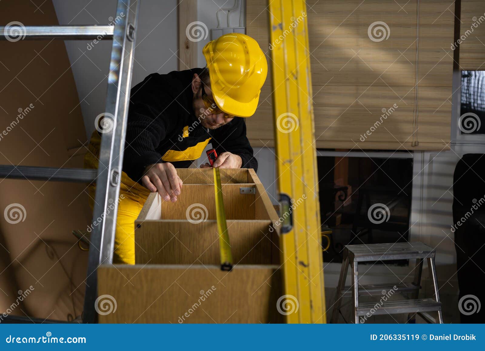A Construction Worker Checks a Pull-out Cupboard at the Top with a Tape ...