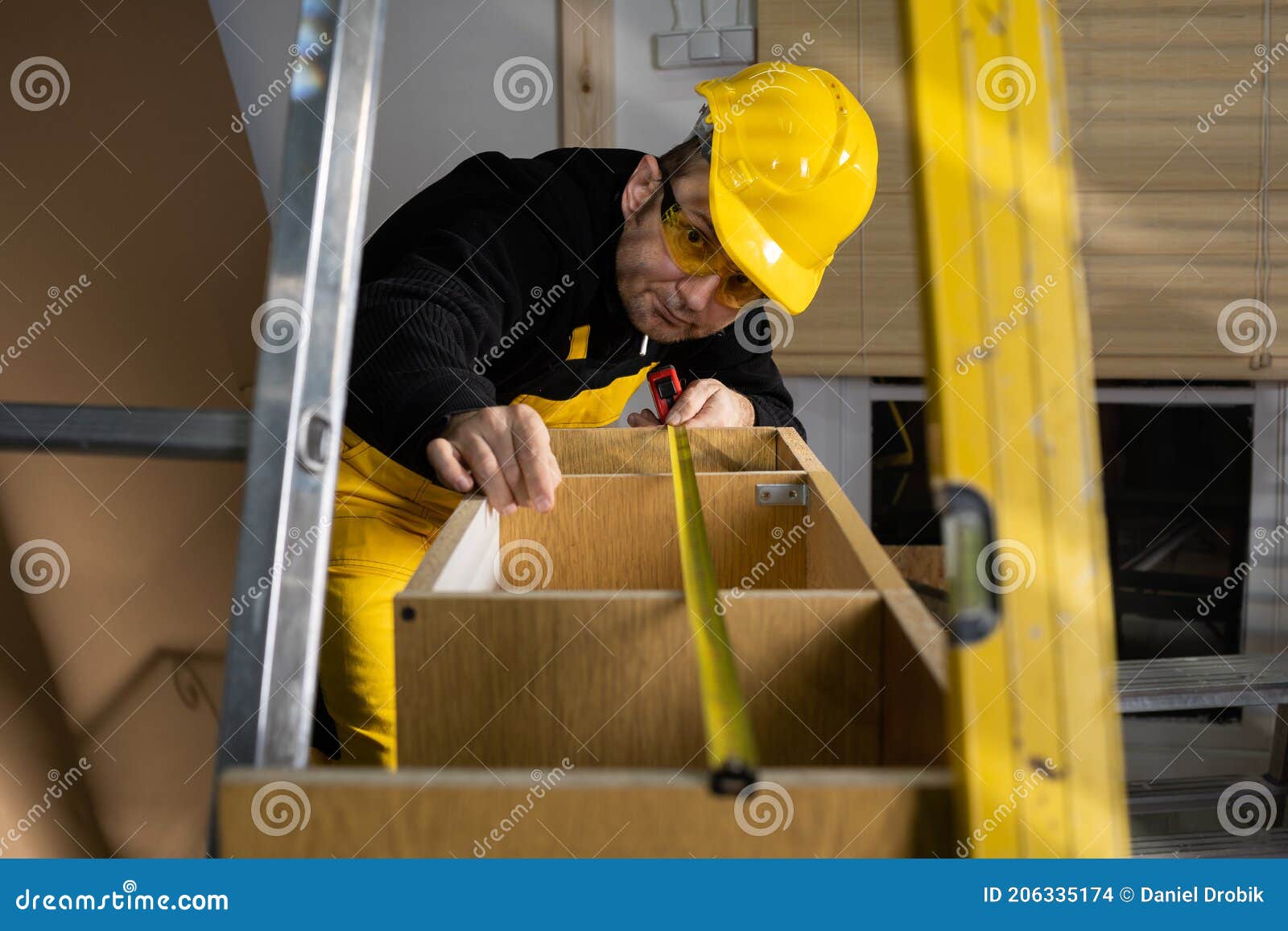 A Construction Worker Checks a Pull-out Cupboard at the Top with a Tape ...